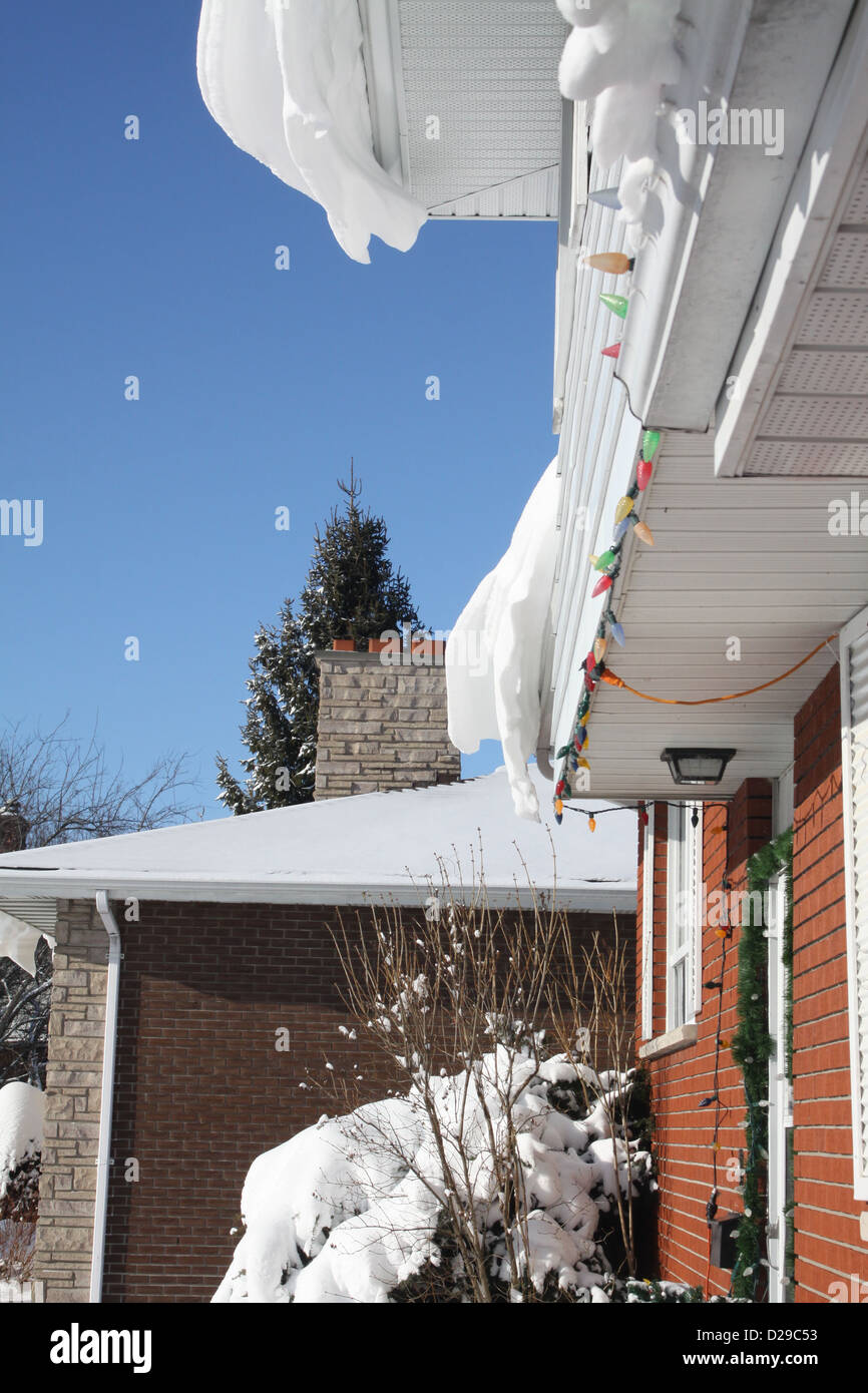 Snow hanging from and over the eaves of a house Stock Photo - Alamy