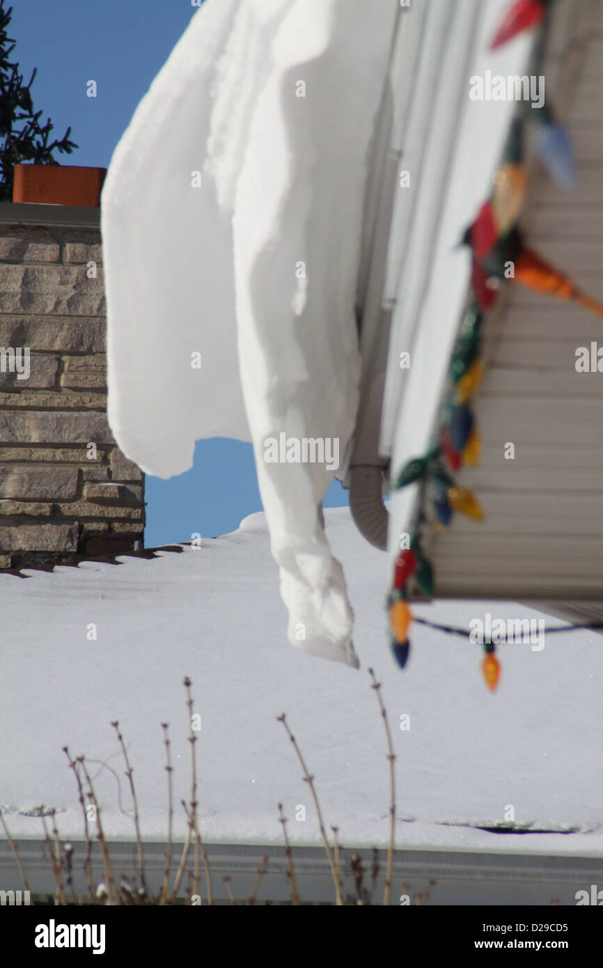 Snow hanging from and over the eaves of a house Stock Photo - Alamy