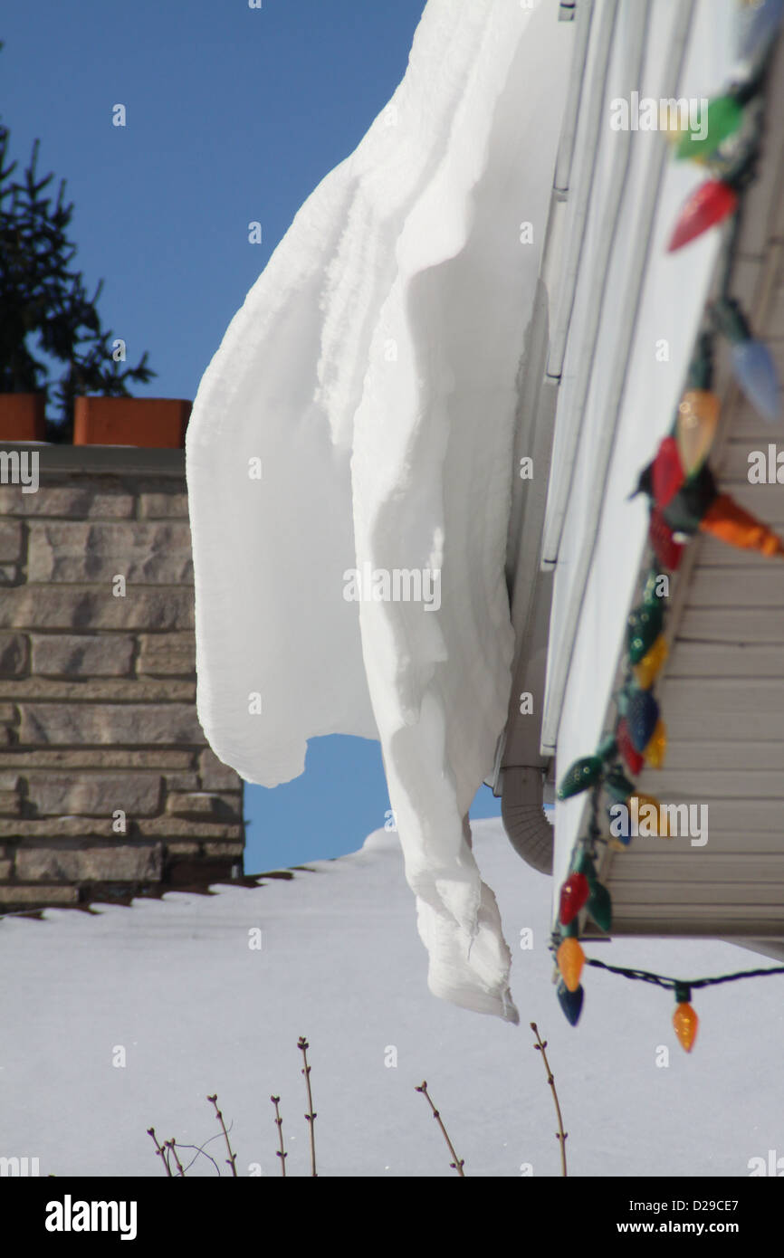 Snow hanging from and over the eaves of a house Stock Photo - Alamy