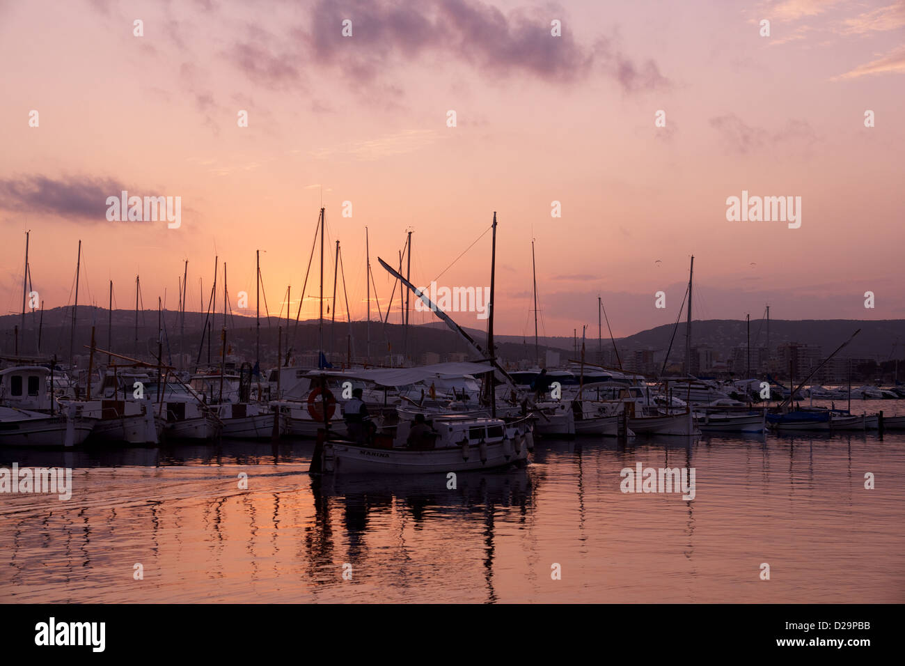 A boat leaving the harbor and sailing off into the sunset Stock Photo ...