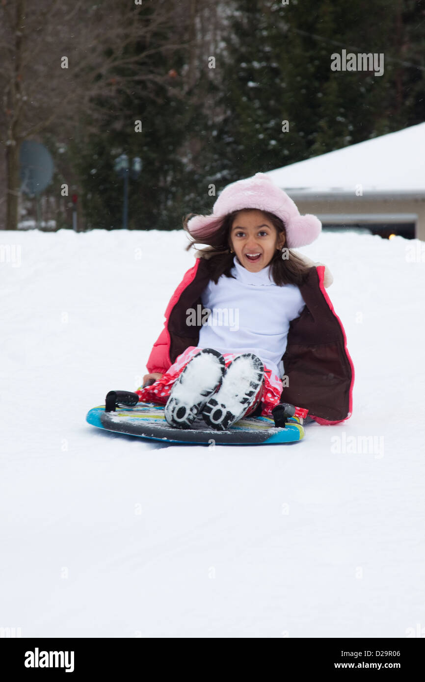 A happy East Indian girl goes down a slope on a toboggan Stock Photo ...