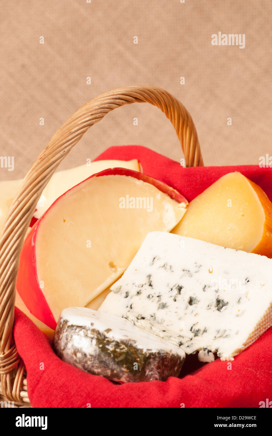 Still life of assorted cheese varieties inside a traditional basket ...