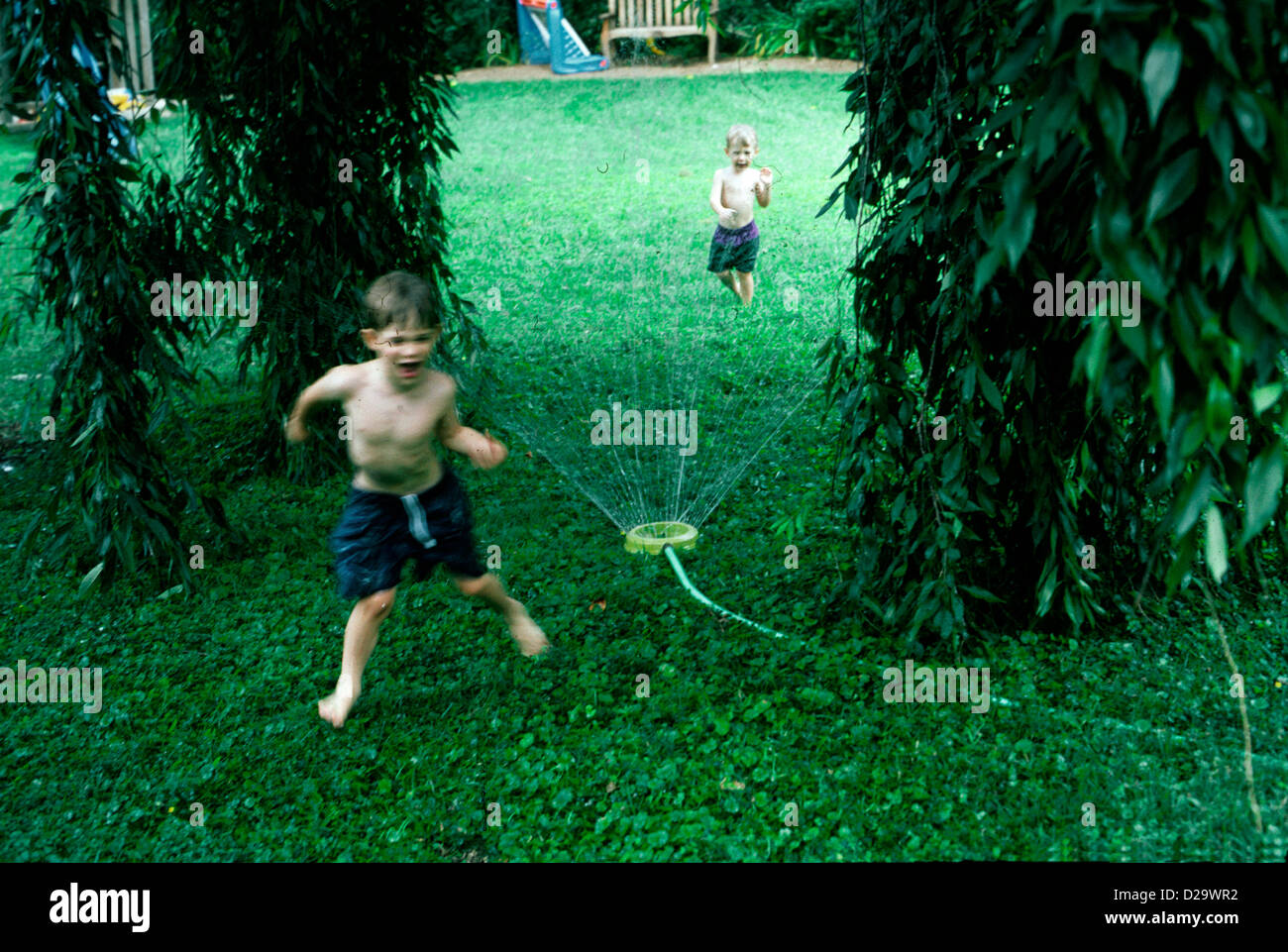 Kids running through sprinkler hi-res stock photography and images - Alamy