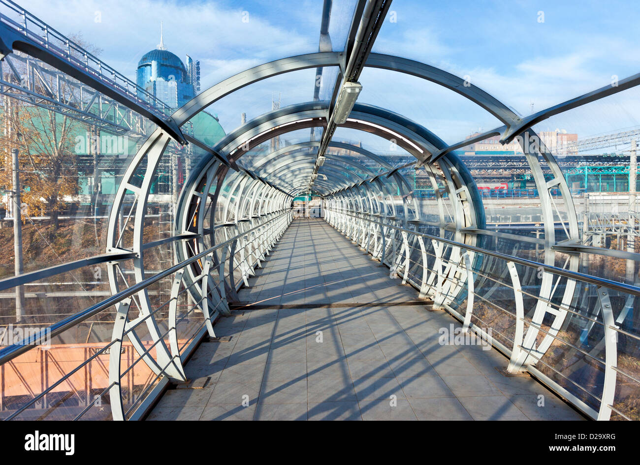 Steel and glass bridge for pedestrians crossing over the railway tracks ...