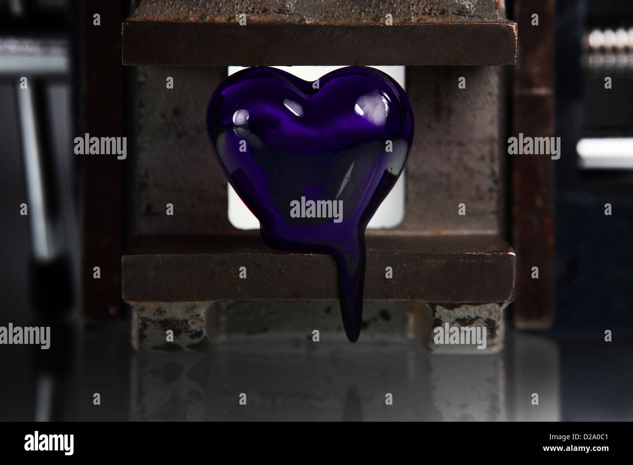 a purple blue heart that melts between the jaws of a vice or press. Low ...