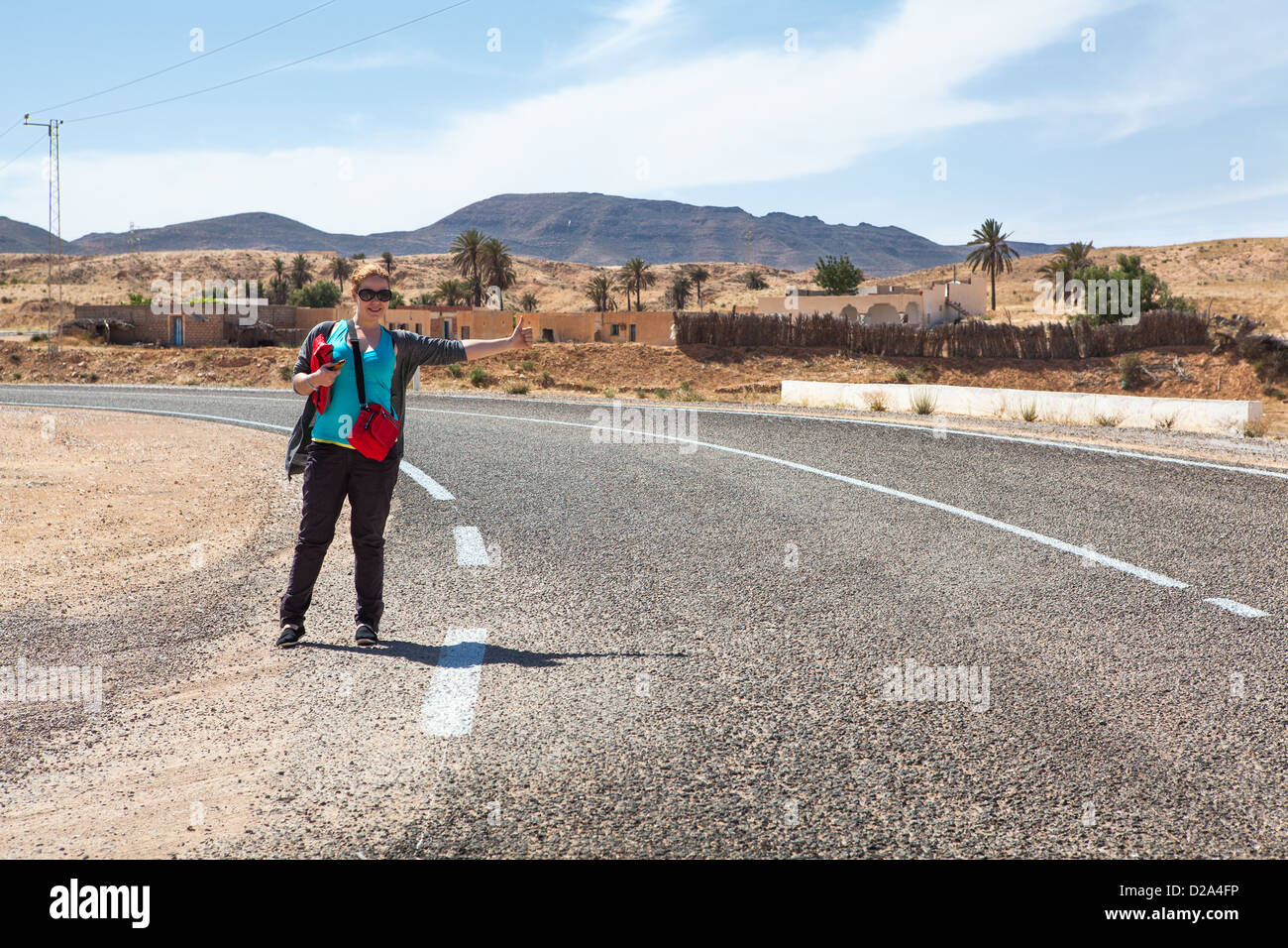 One woman on road with thumb lift up for hitching car Stock Photo - Alamy