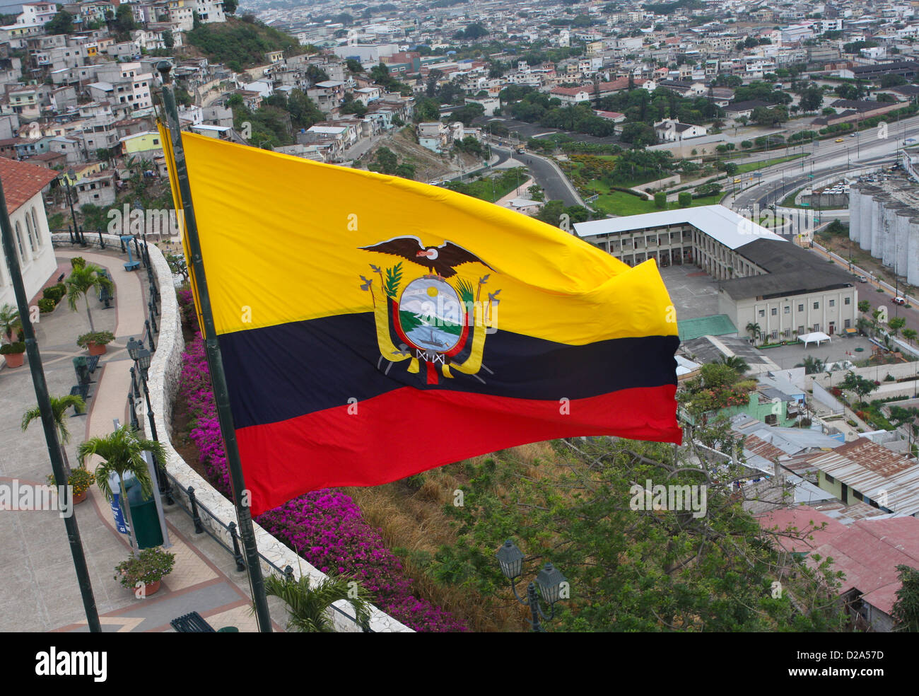 An Ecuadorian flag with yellow, blue and red strips flying over a city ...