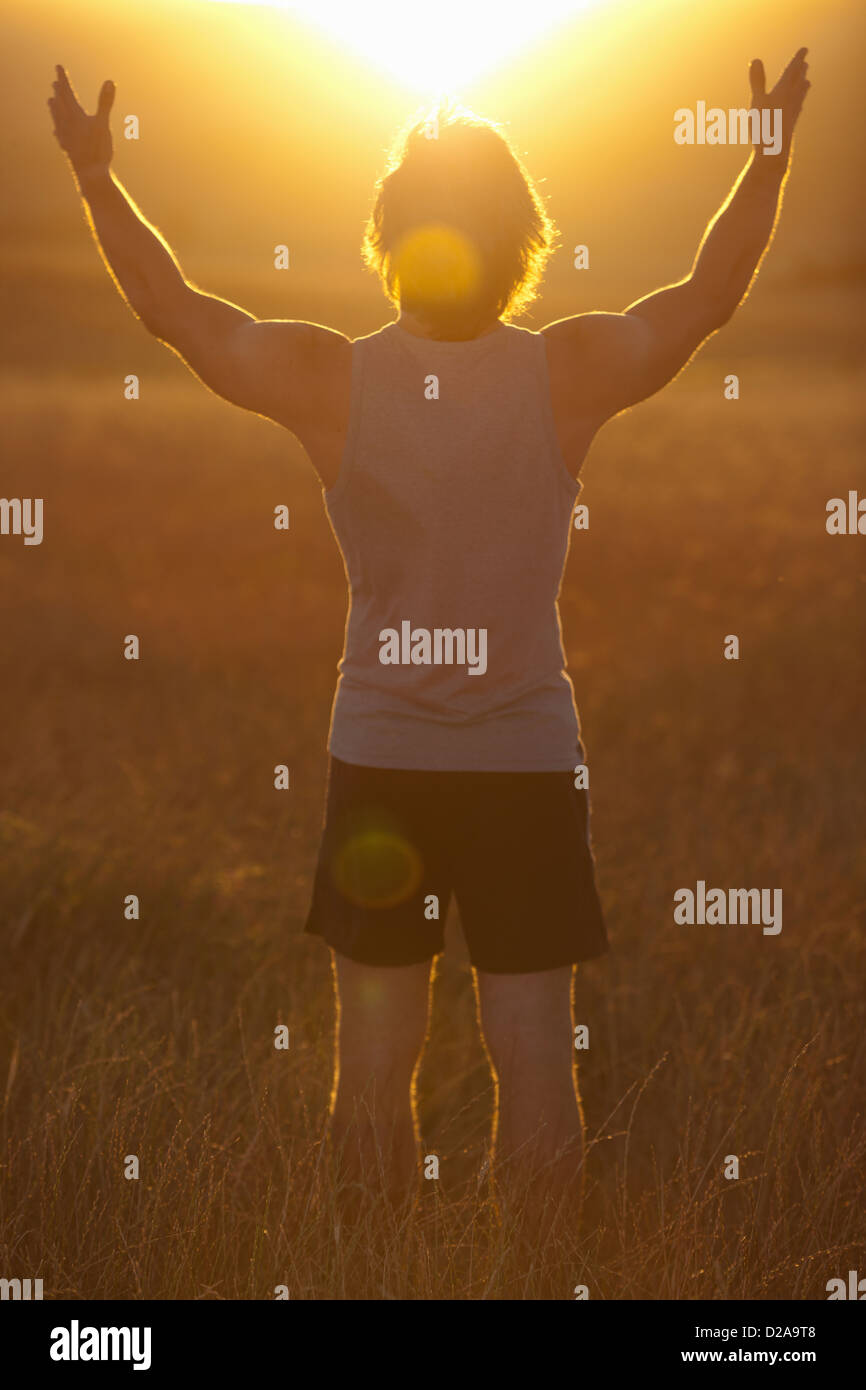 Man standing in field at sunset Stock Photo - Alamy