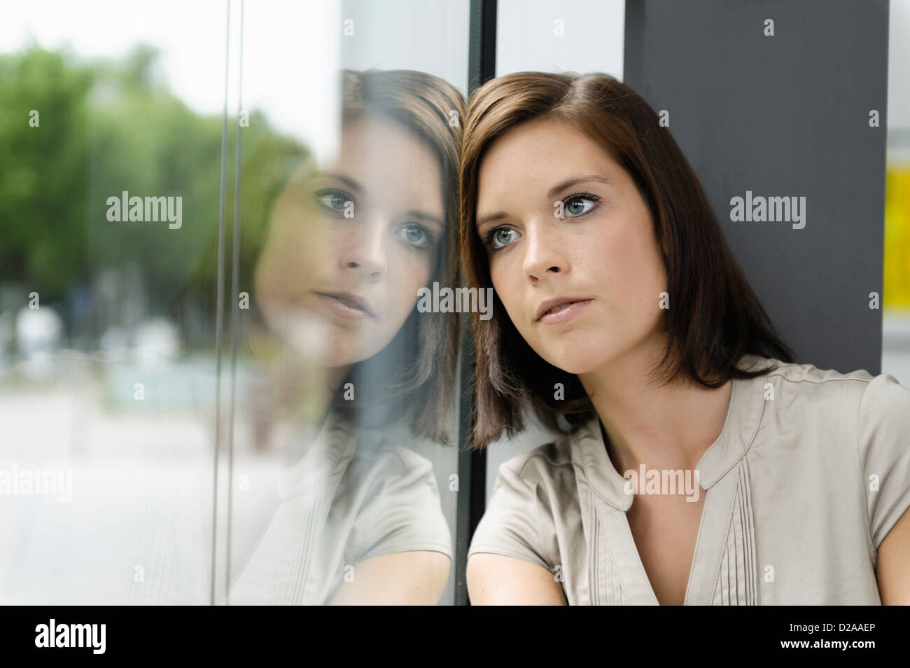 Businesswoman leaning against window Stock Photo - Alamy