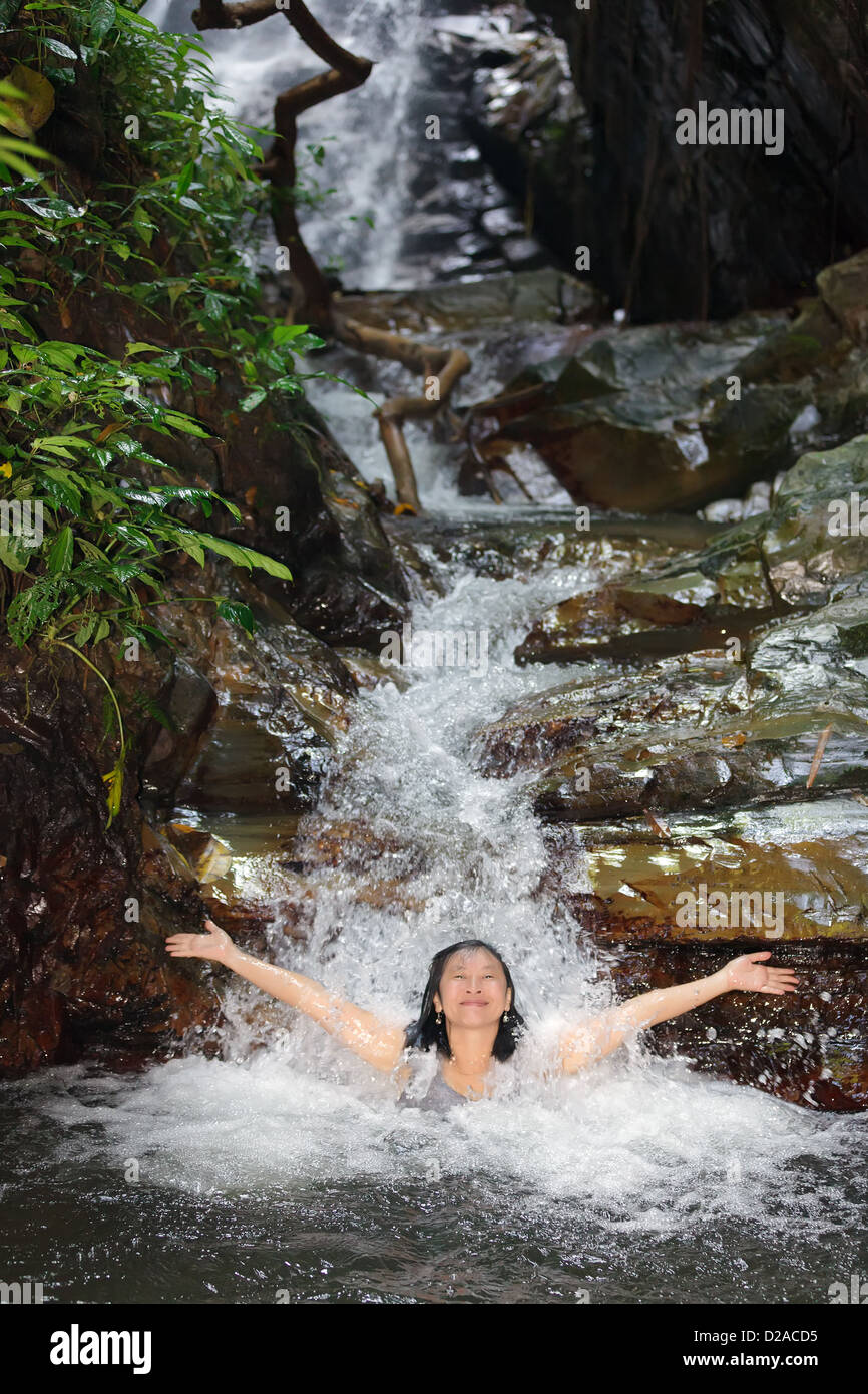 Happy woman enjoying freshness of wild waterfall, Thailand Stock Photo ...