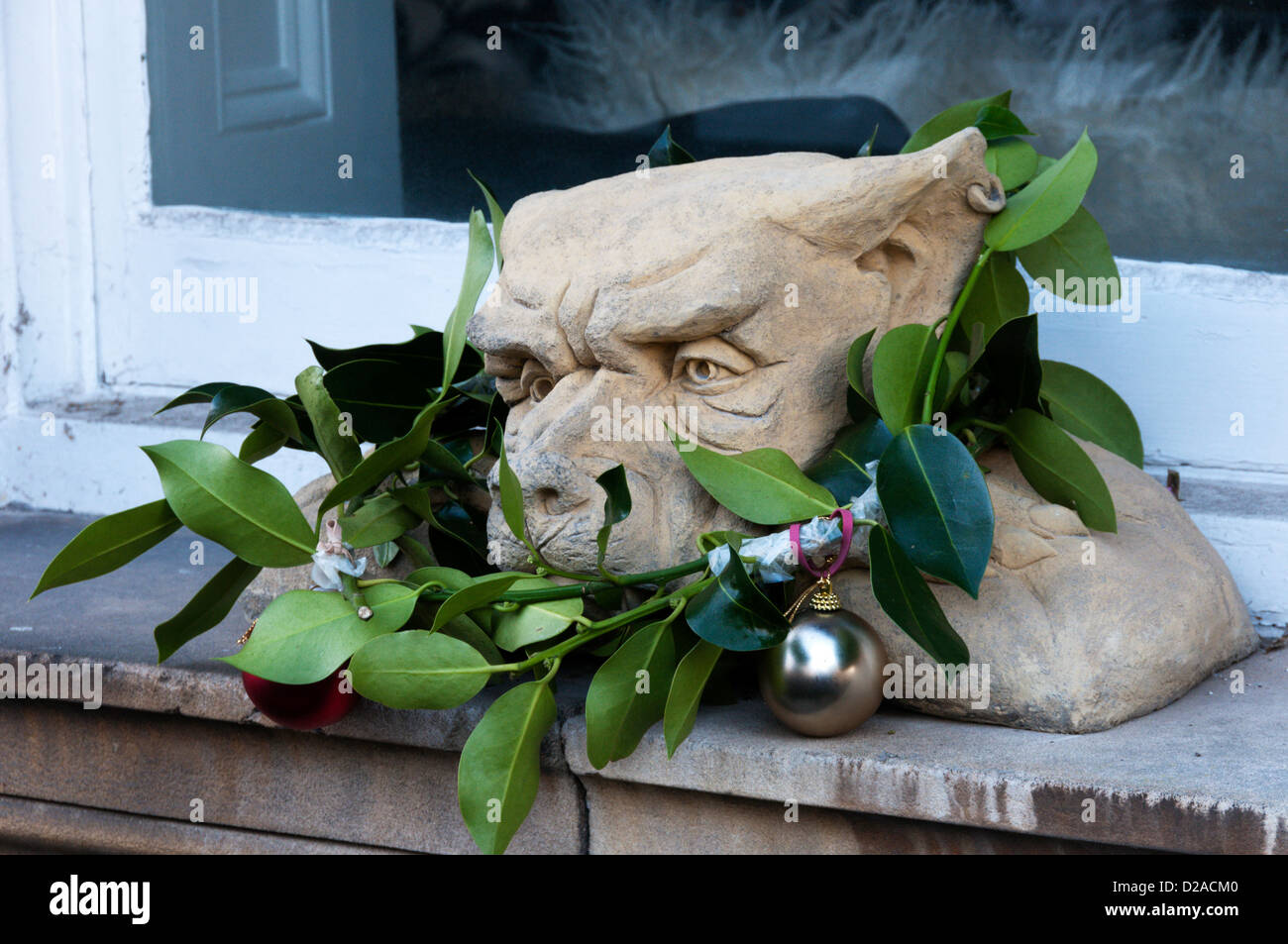 A gargoyle on a windowsill decorated for Christmas Stock Photo - Alamy