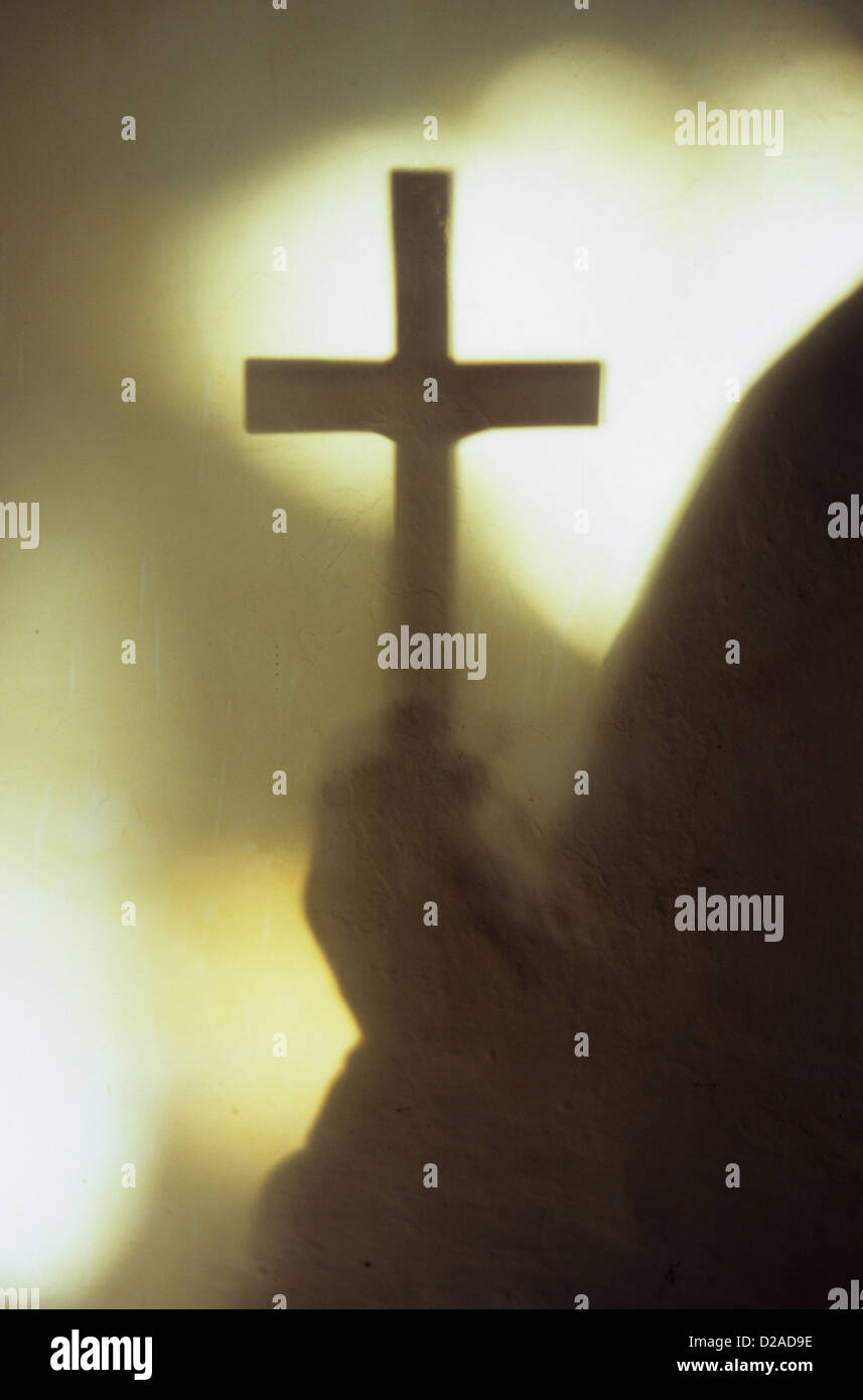 Shadow of hooded monk or priest holding plain crucifix in front of ...