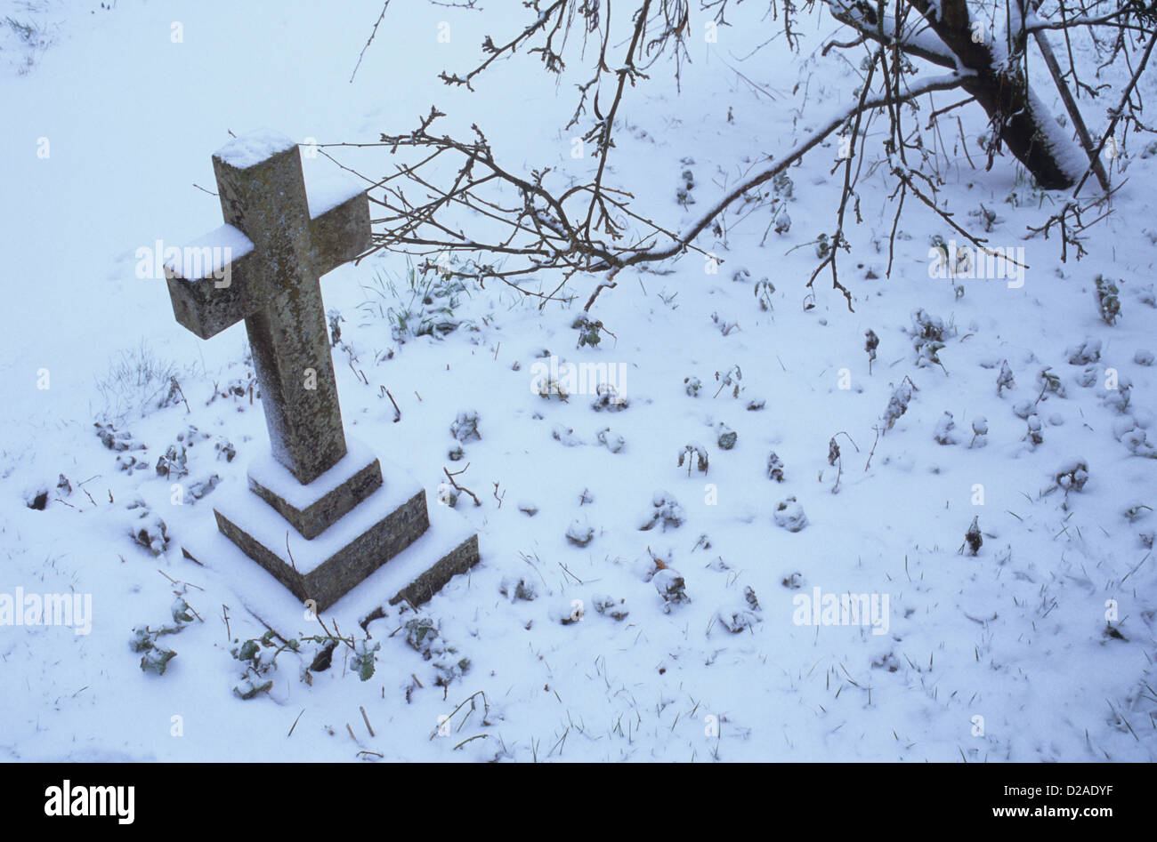Marble crucifix gravestone on stepped marble plinth dusted with snow ...