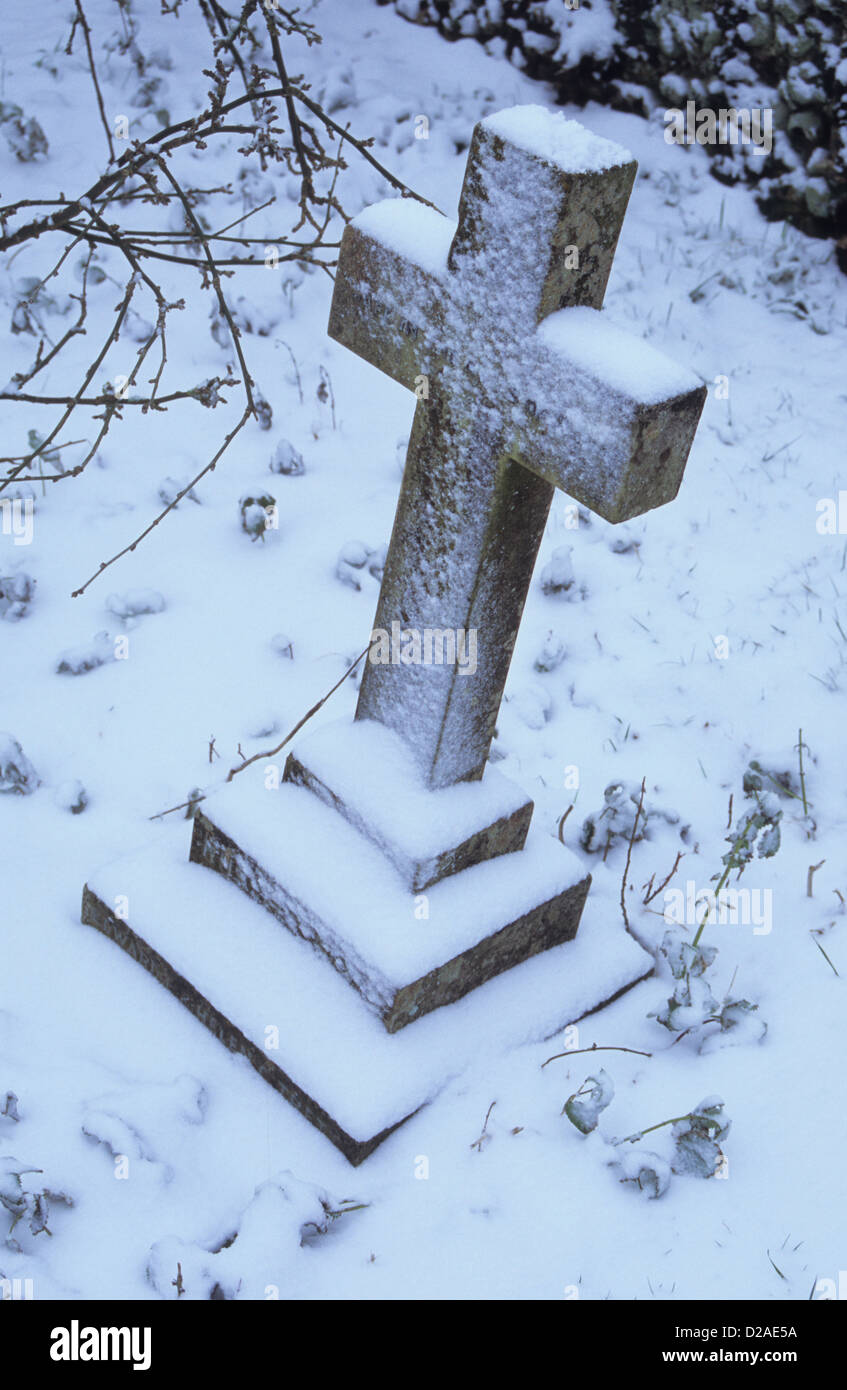 Marble crucifix gravestone on stepped marble plinth dusted with snow ...