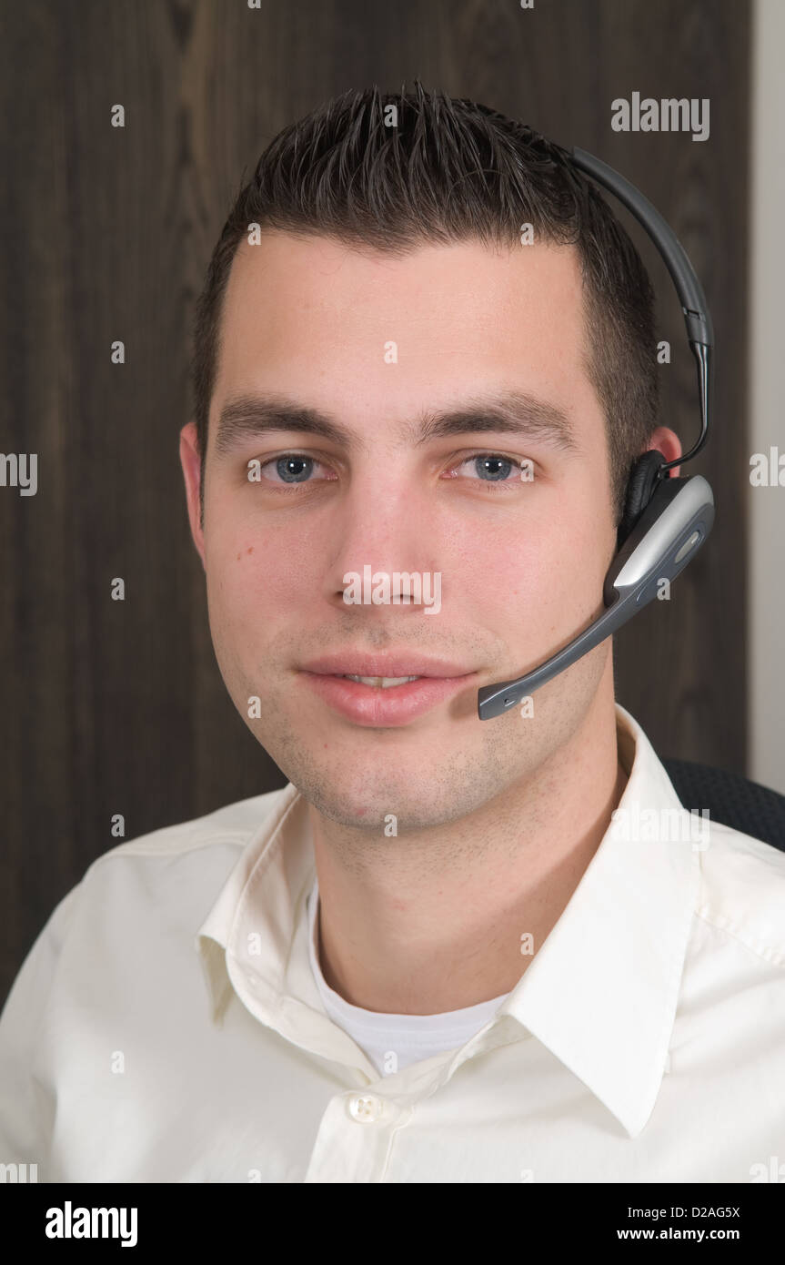 Male receptionist working at a helpdesk in an office Stock Photo - Alamy