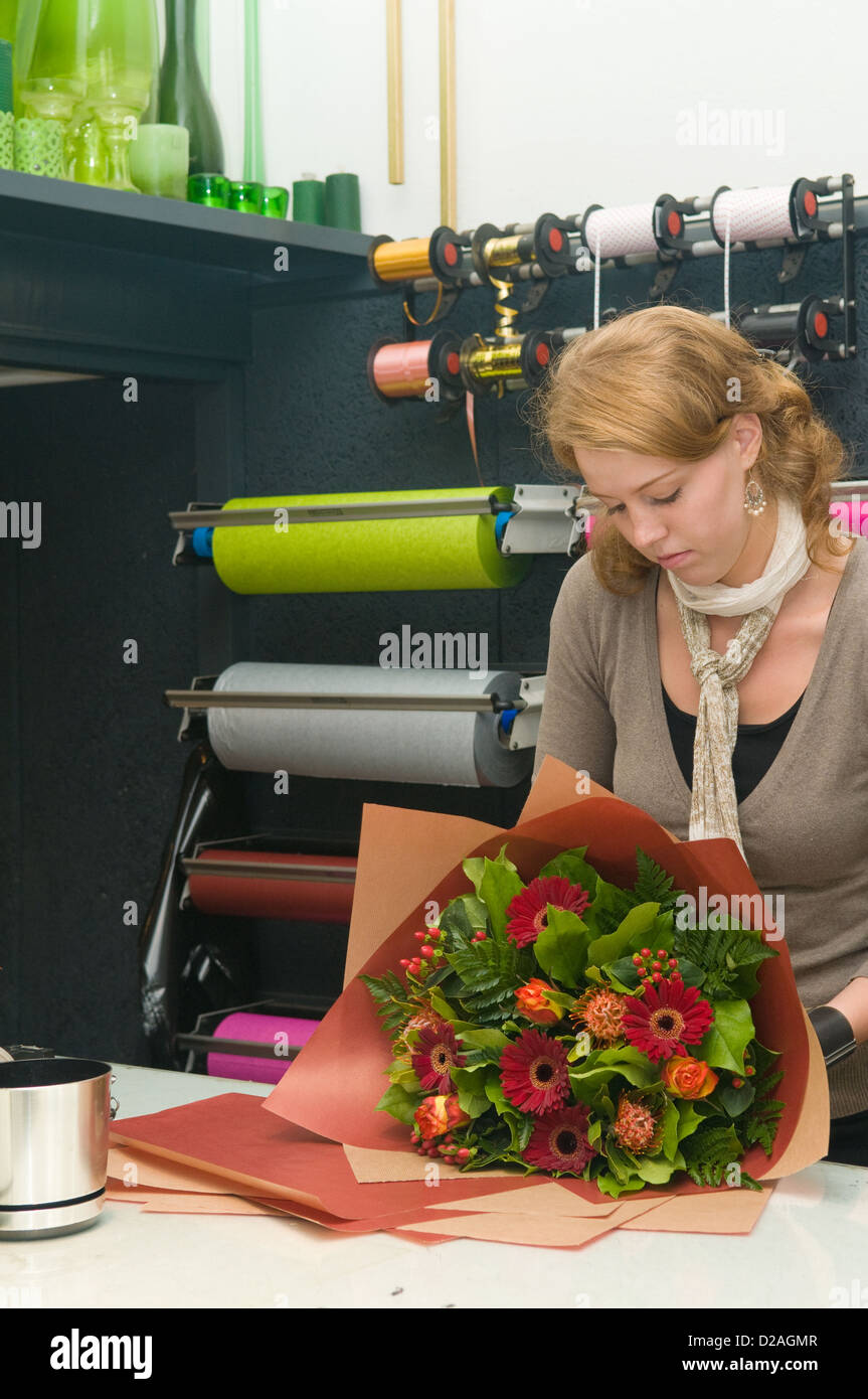 Female florist working in a flower store, making the bouquet ready for ...
