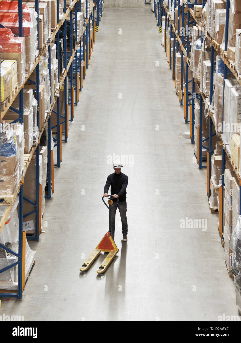 Worker operating dolly in warehouse Stock Photo - Alamy