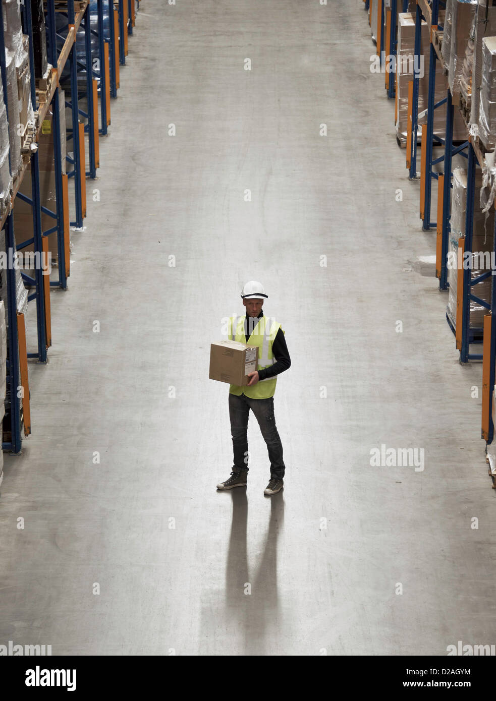 Worker carrying box in warehouse Stock Photo - Alamy