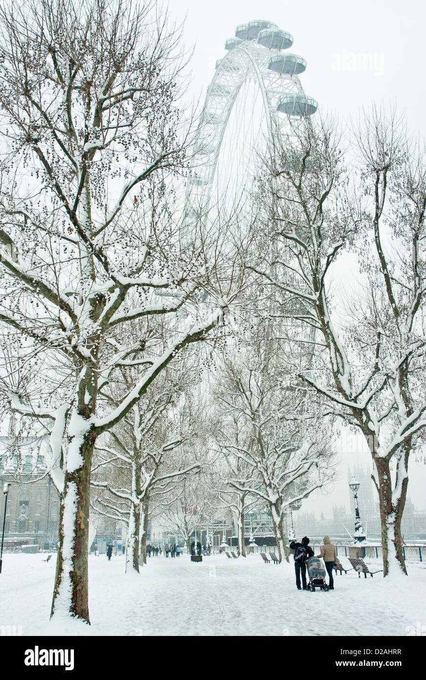 Snowy winter scene with the London Eye/ Wheel, trees, and pavement ...