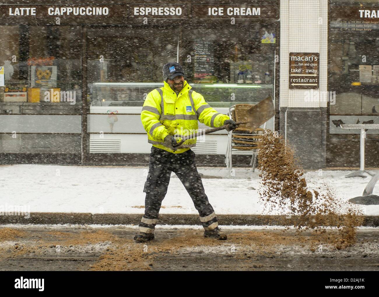 Manual road gritting in front of a seafront coffee shop and ice cream ...