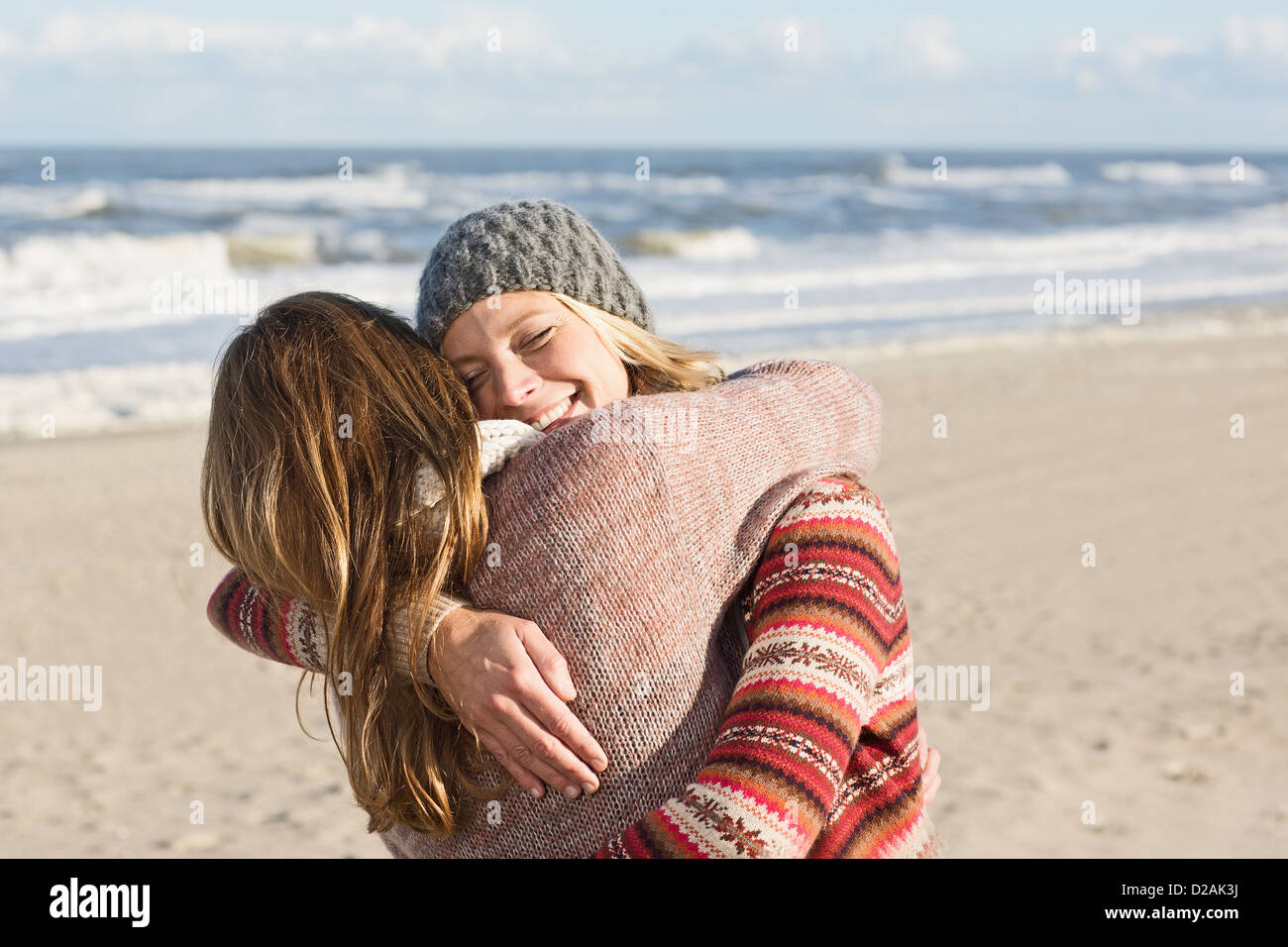 Smiling women hugging on beach Stock Photo - Alamy