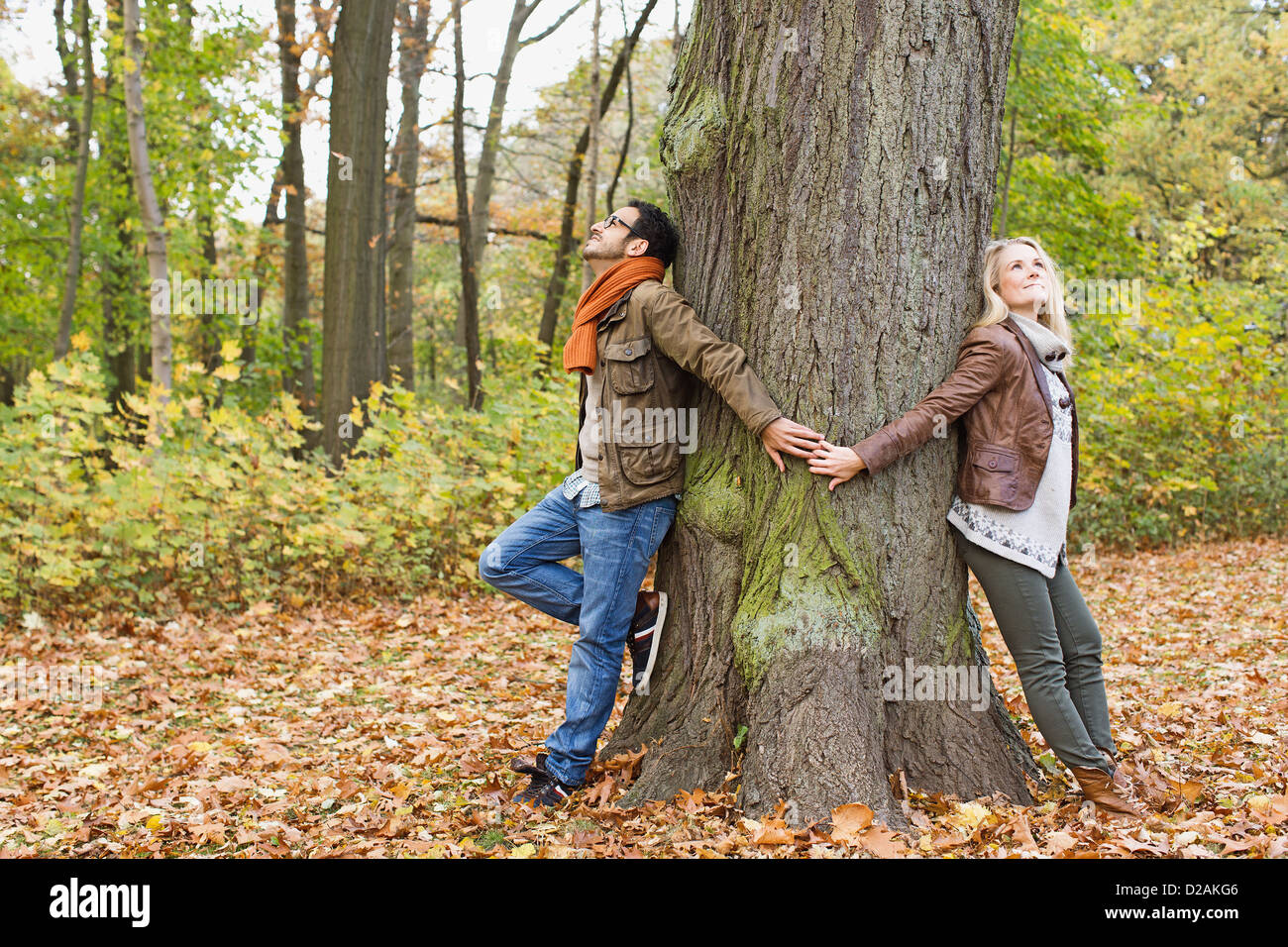 Couple holding hands around tree Stock Photo - Alamy