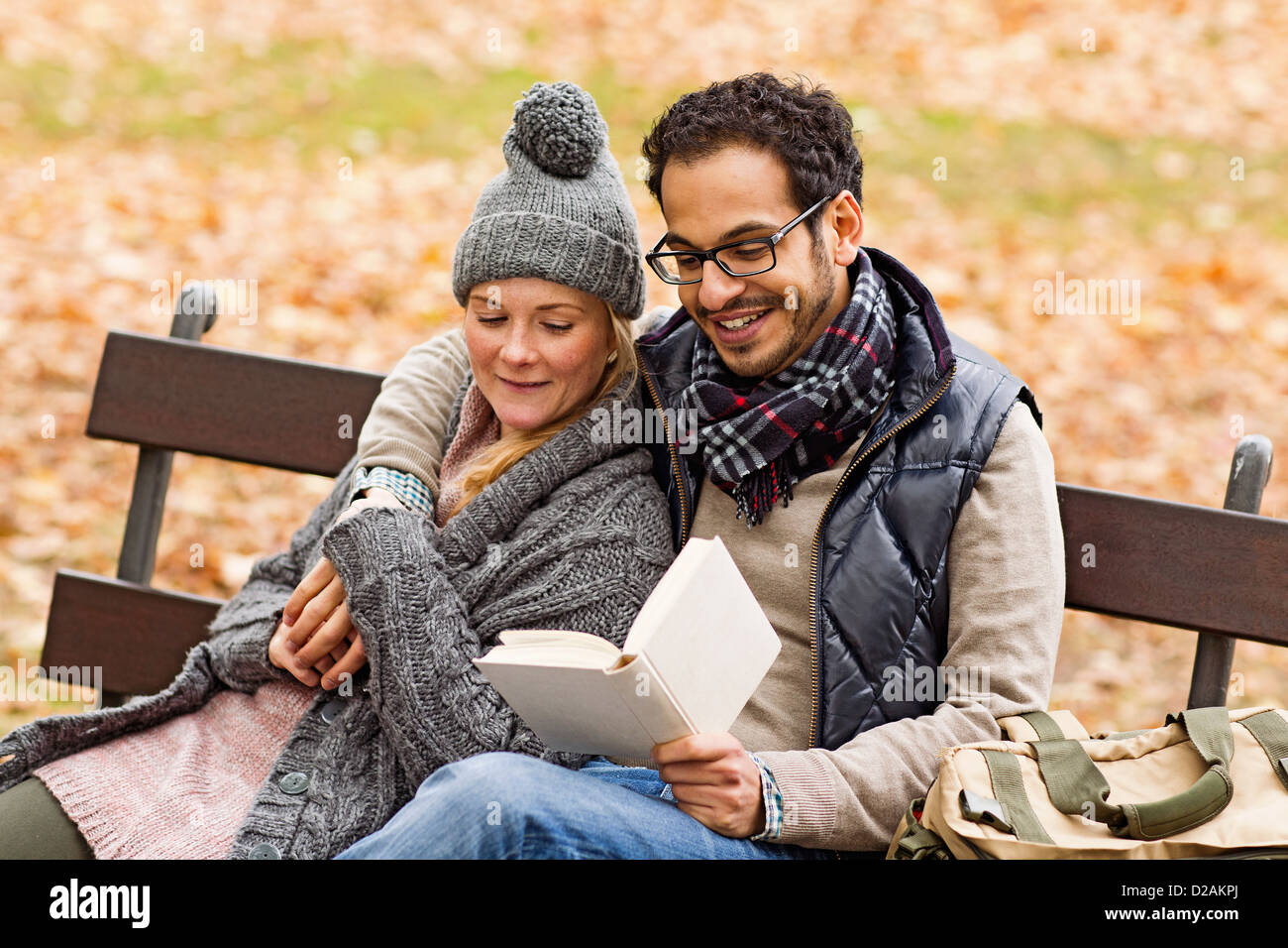 Couple reading together on park bench Stock Photo - Alamy