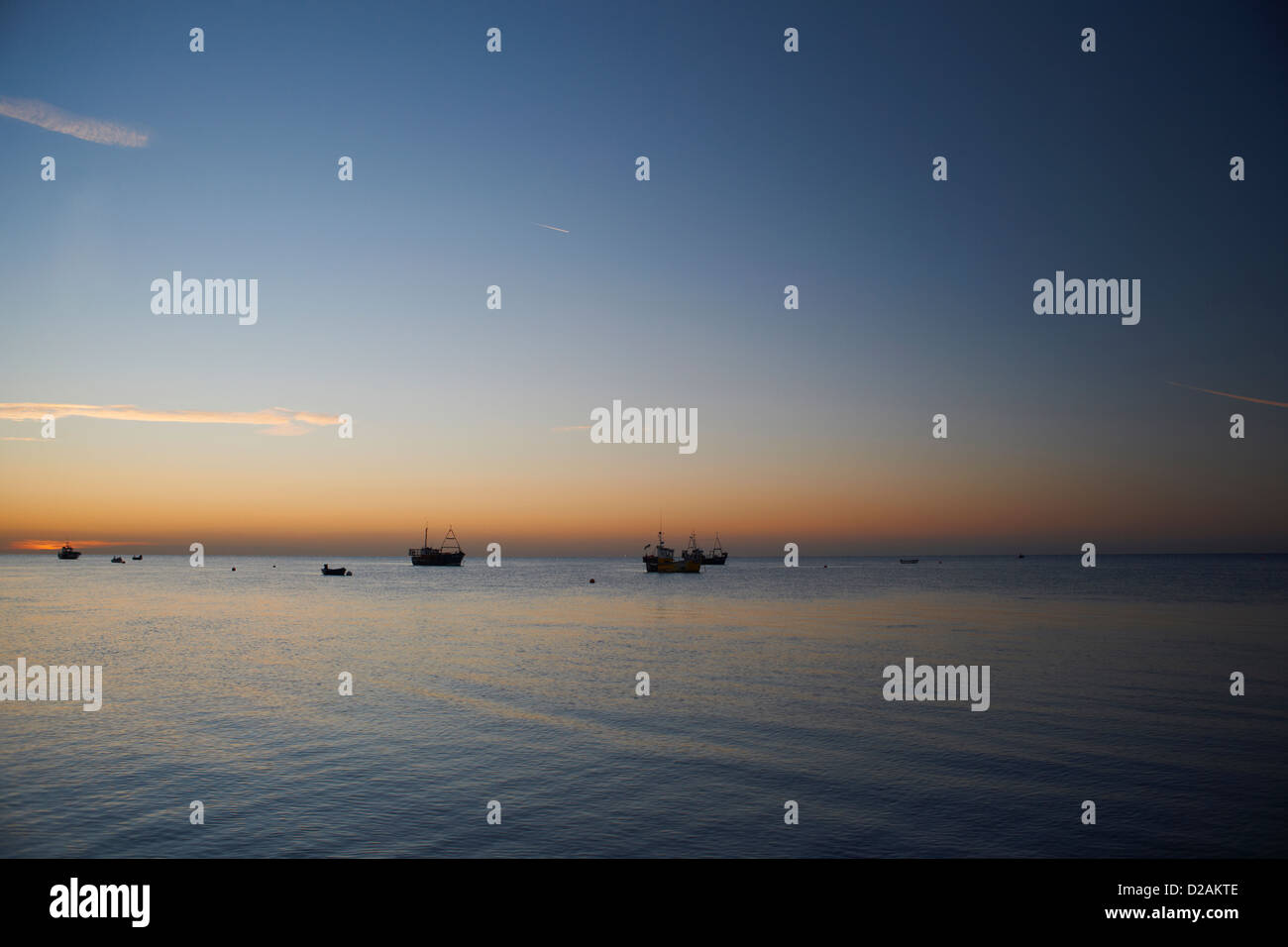 Boats sailing on calm water at sunset Stock Photo - Alamy