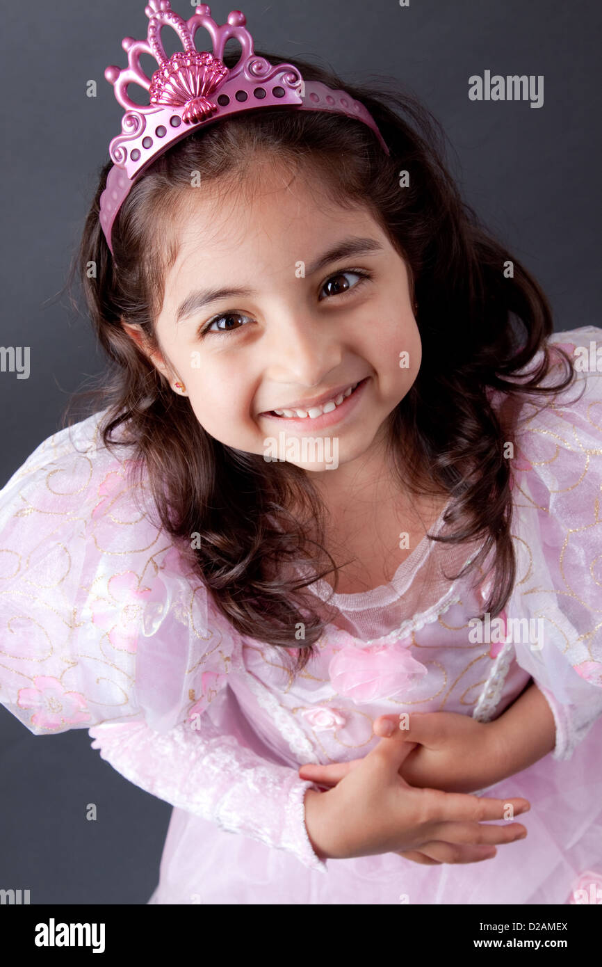 A beautiful girl child smiles as she dresses in her princess costume ...