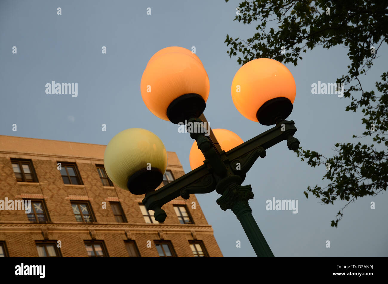 An illuminated street light in front of a brick building at dusk Stock ...