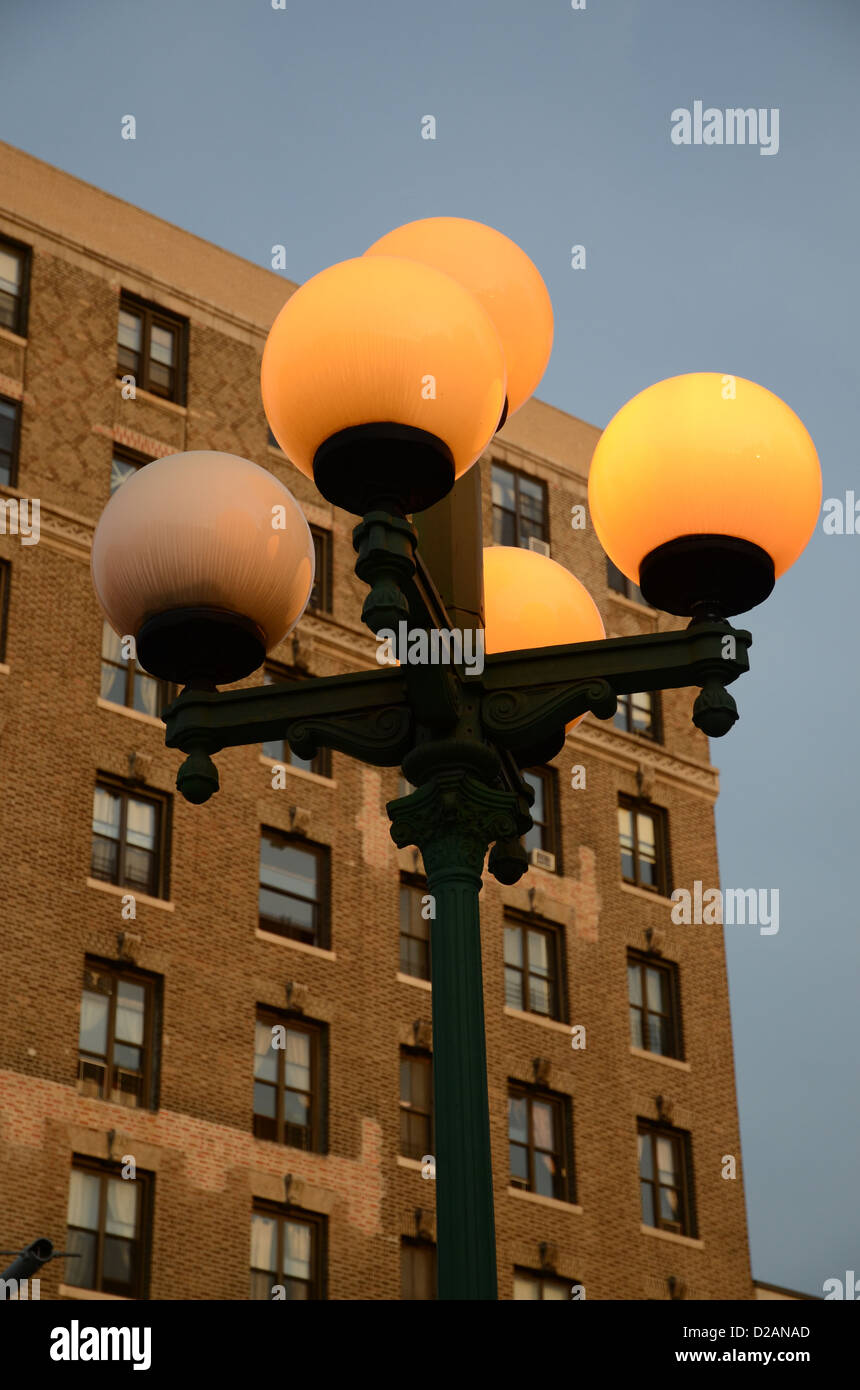 An illuminated street light in front of a brick building at dusk Stock ...