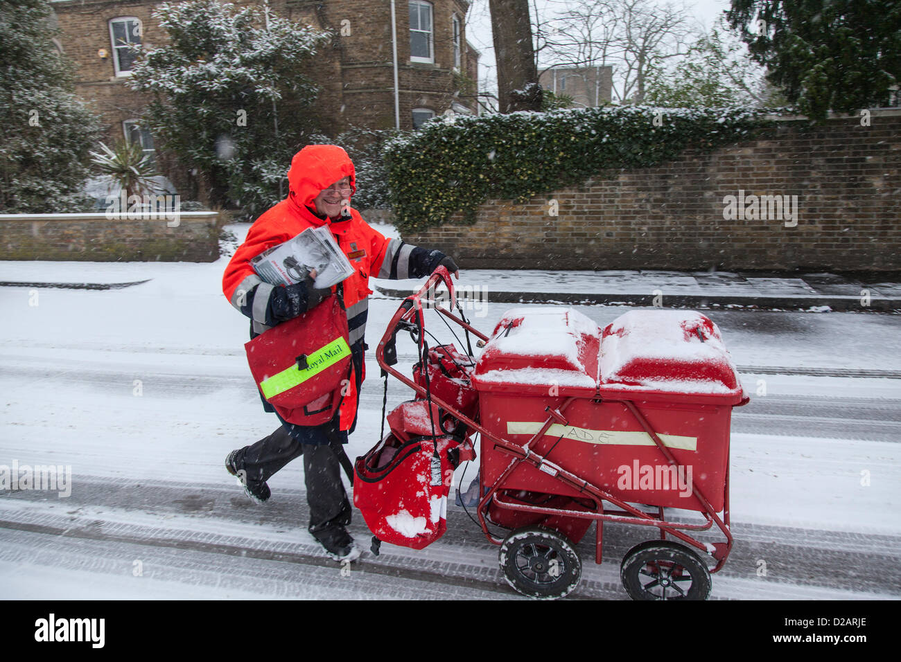 Postman delivering mail in winter Stock Photo - Alamy