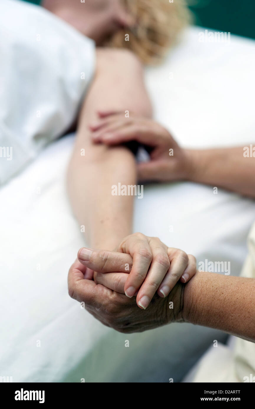 Massage therapist gently holding the hand of her client as she probes ...
