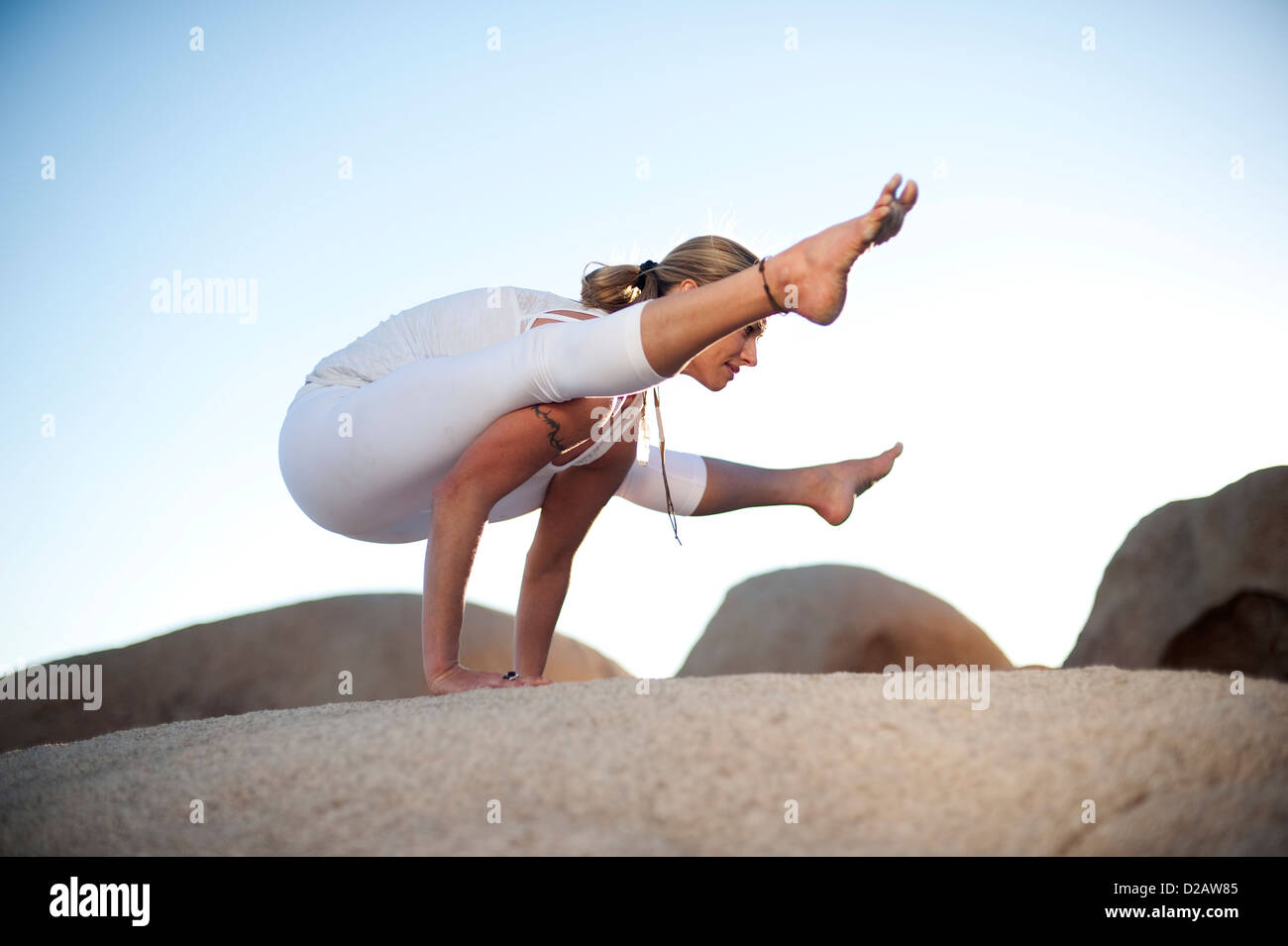 Woman in Titibasana or Firefly yoga posture in a natural boulder ...