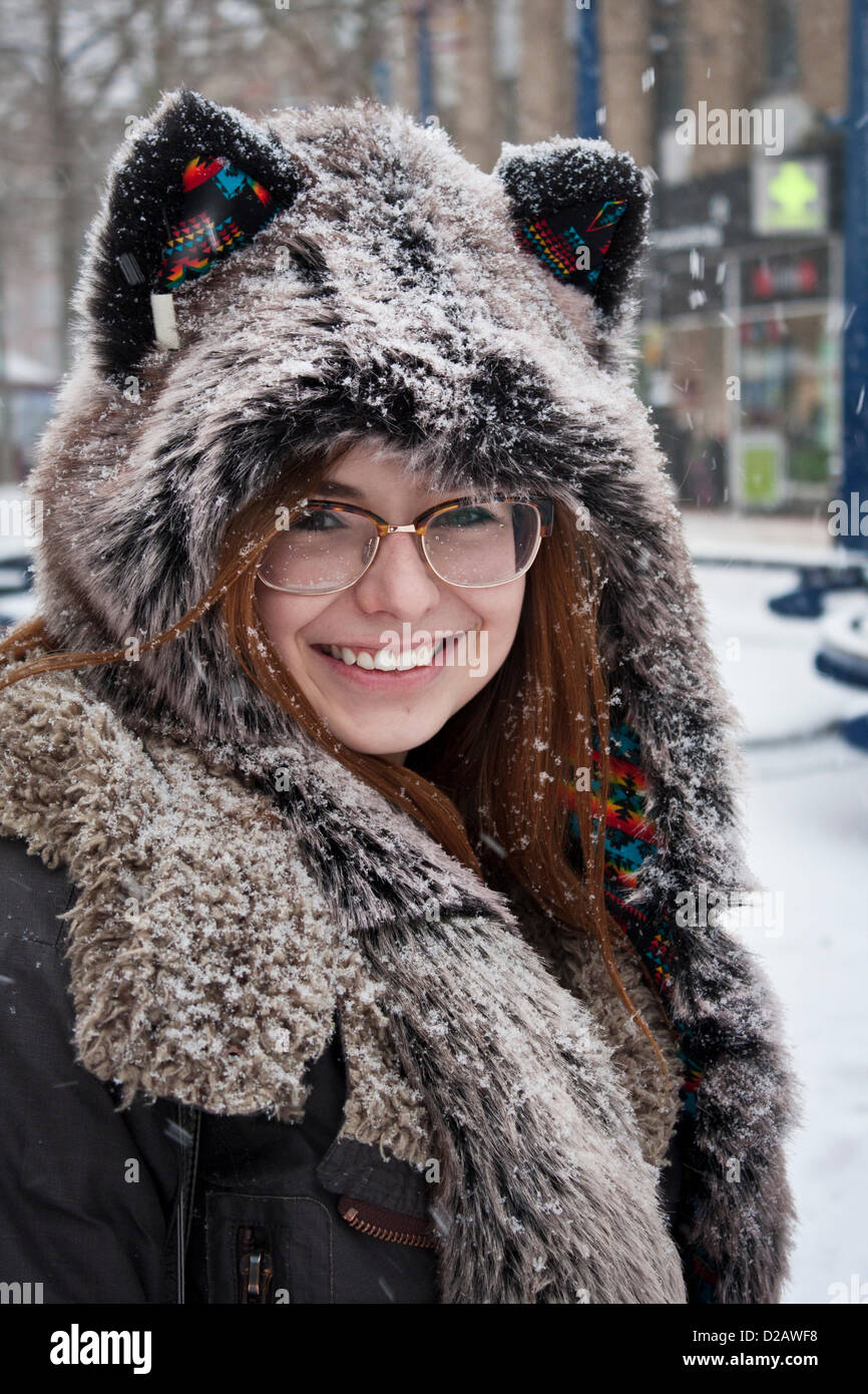 Young woman wears an exotic hat to keep her warm in the snow. Reading ...