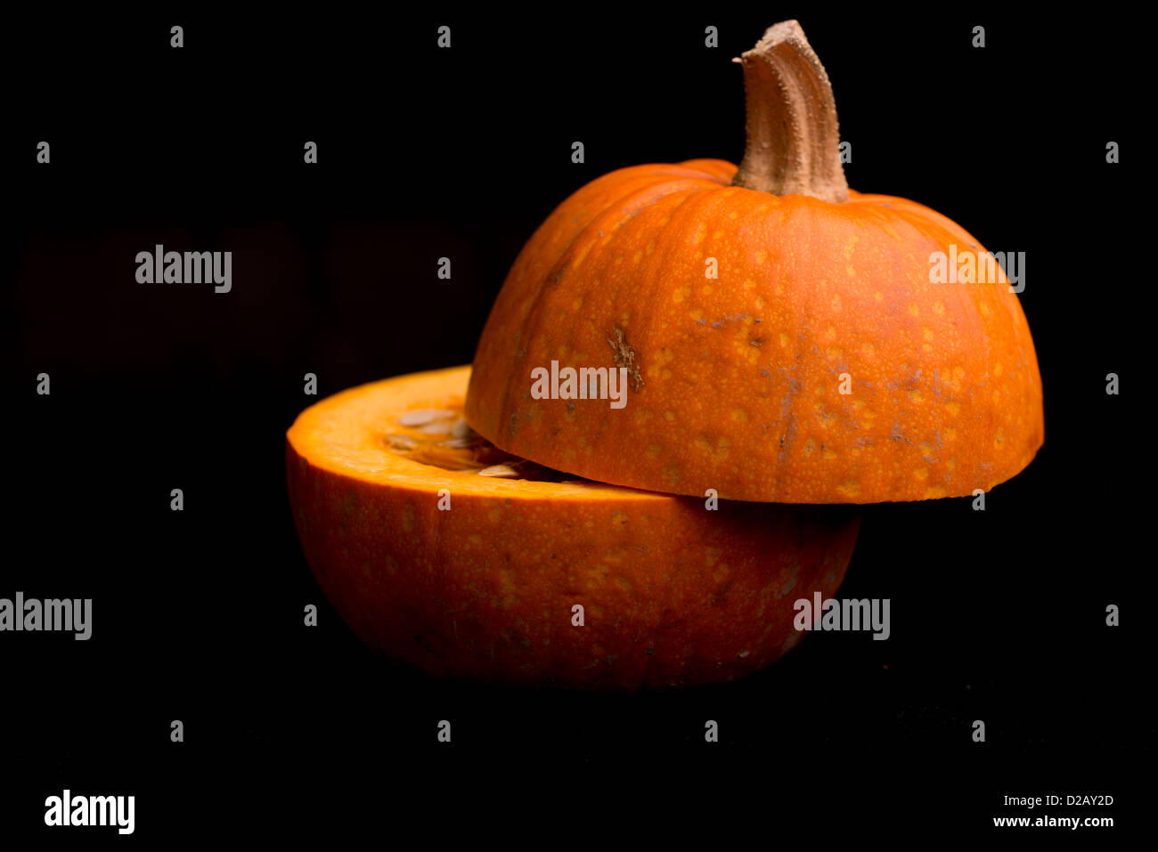 Pumpkin sliced in the middle against black background Stock Photo - Alamy