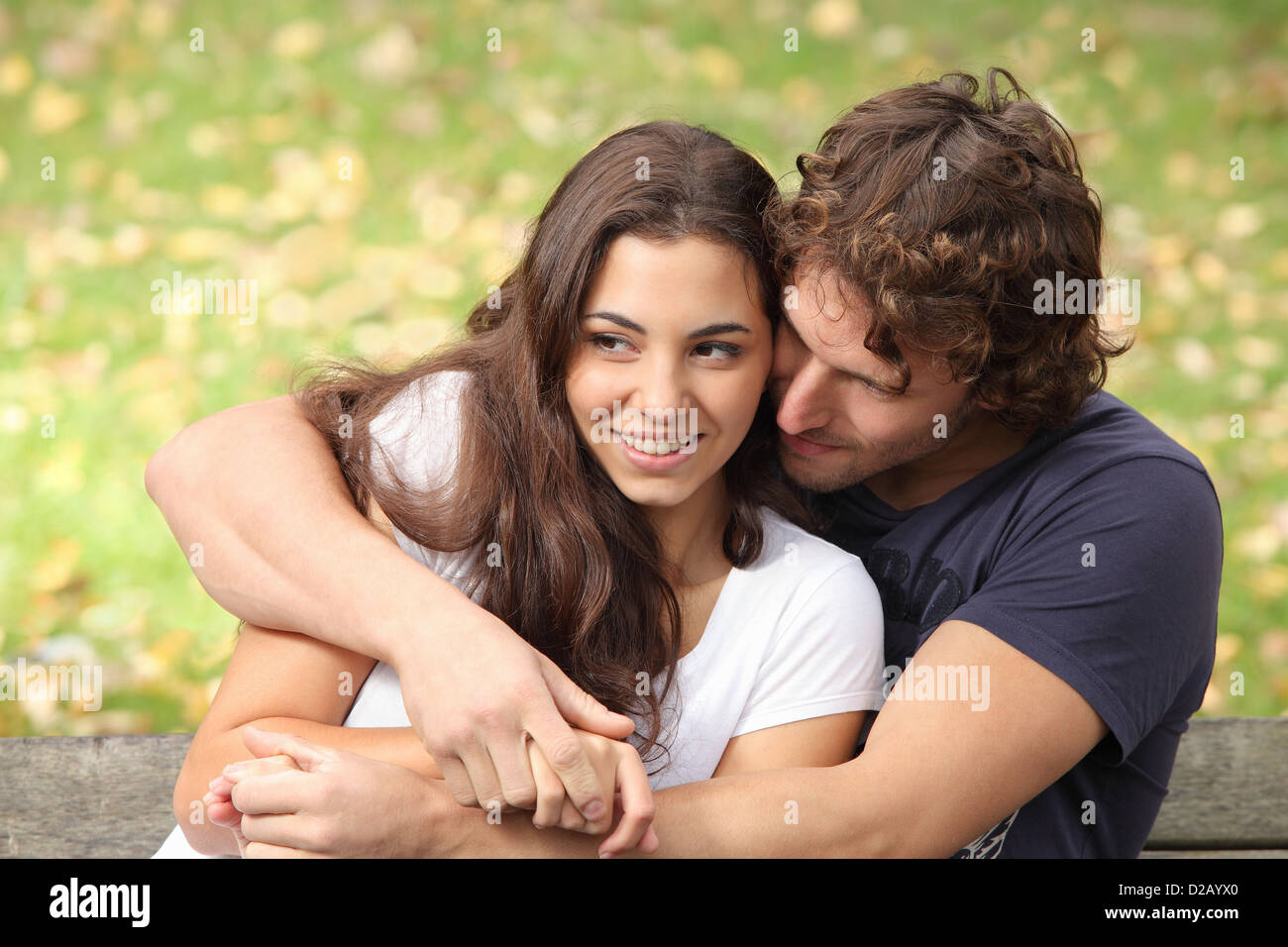 Couple hugging in a park seated in a bench Stock Photo - Alamy