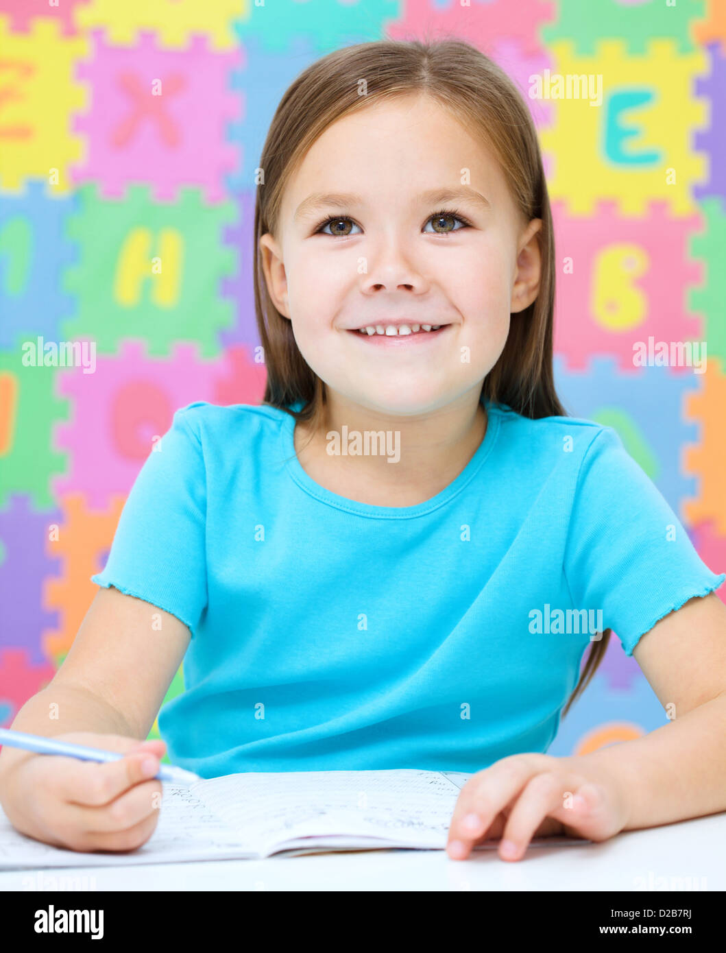 Cute little girl is writing using a pen in preschool Stock Photo - Alamy