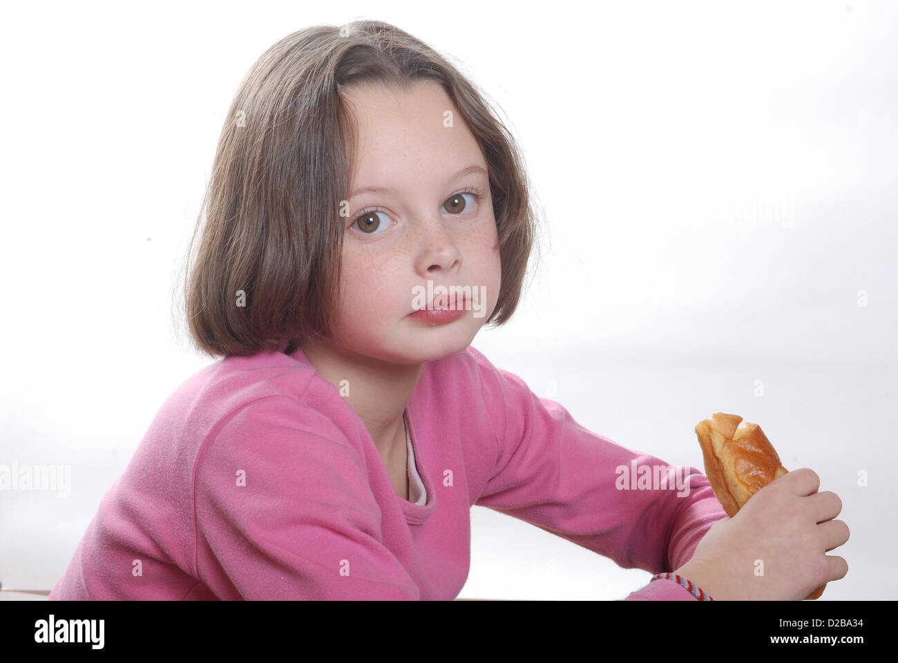 A young girl eating a bun Stock Photo - Alamy