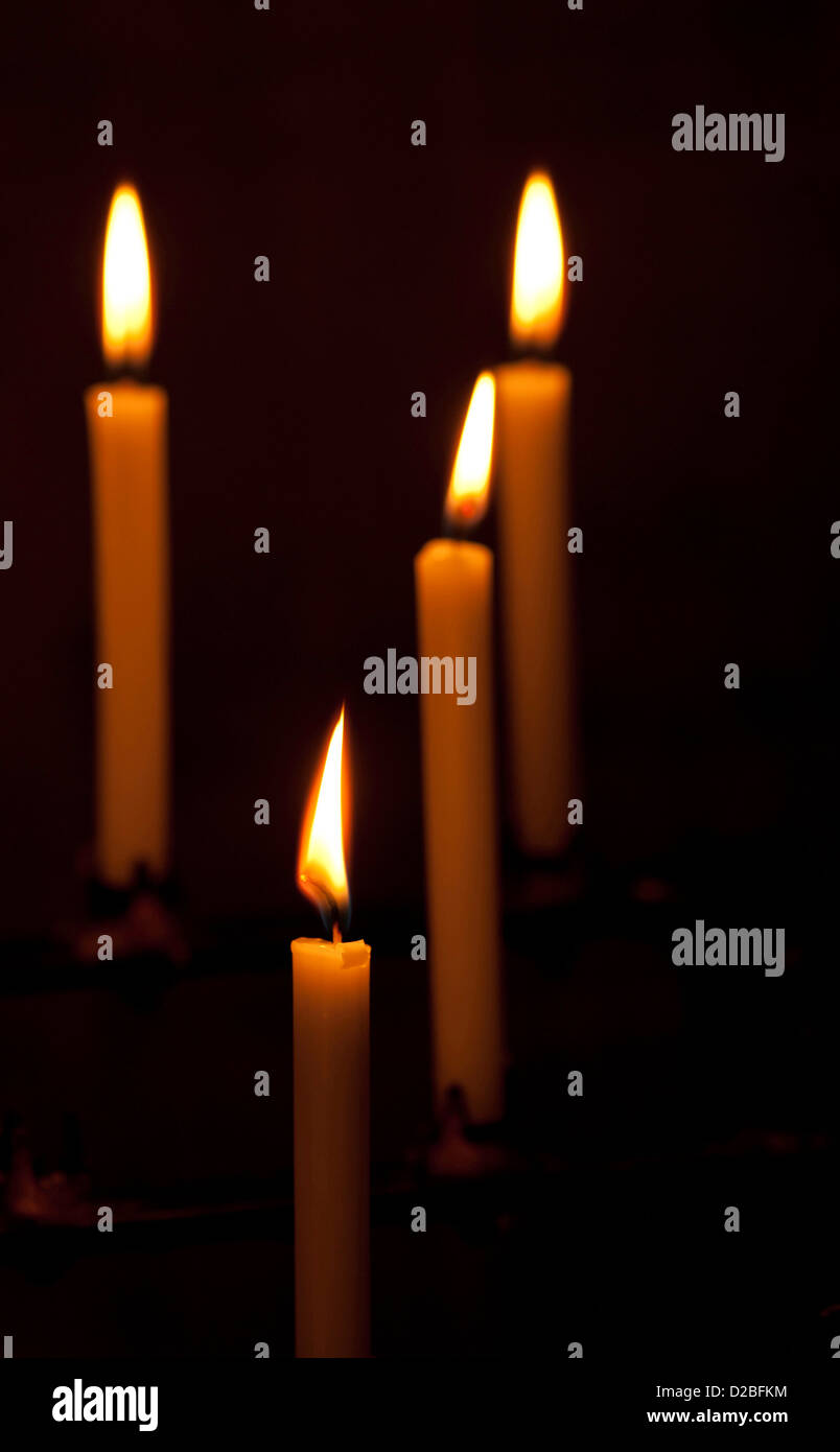 Four Prayer Candles against a dark background, focus on the front ...