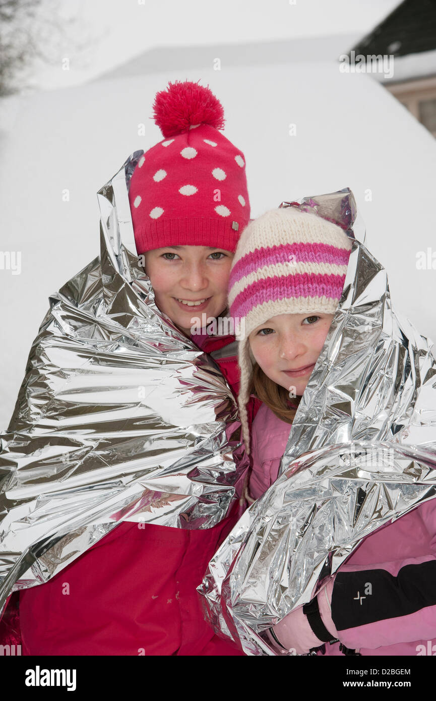 Young children huddle up using a foil blanket following a snowfall in ...