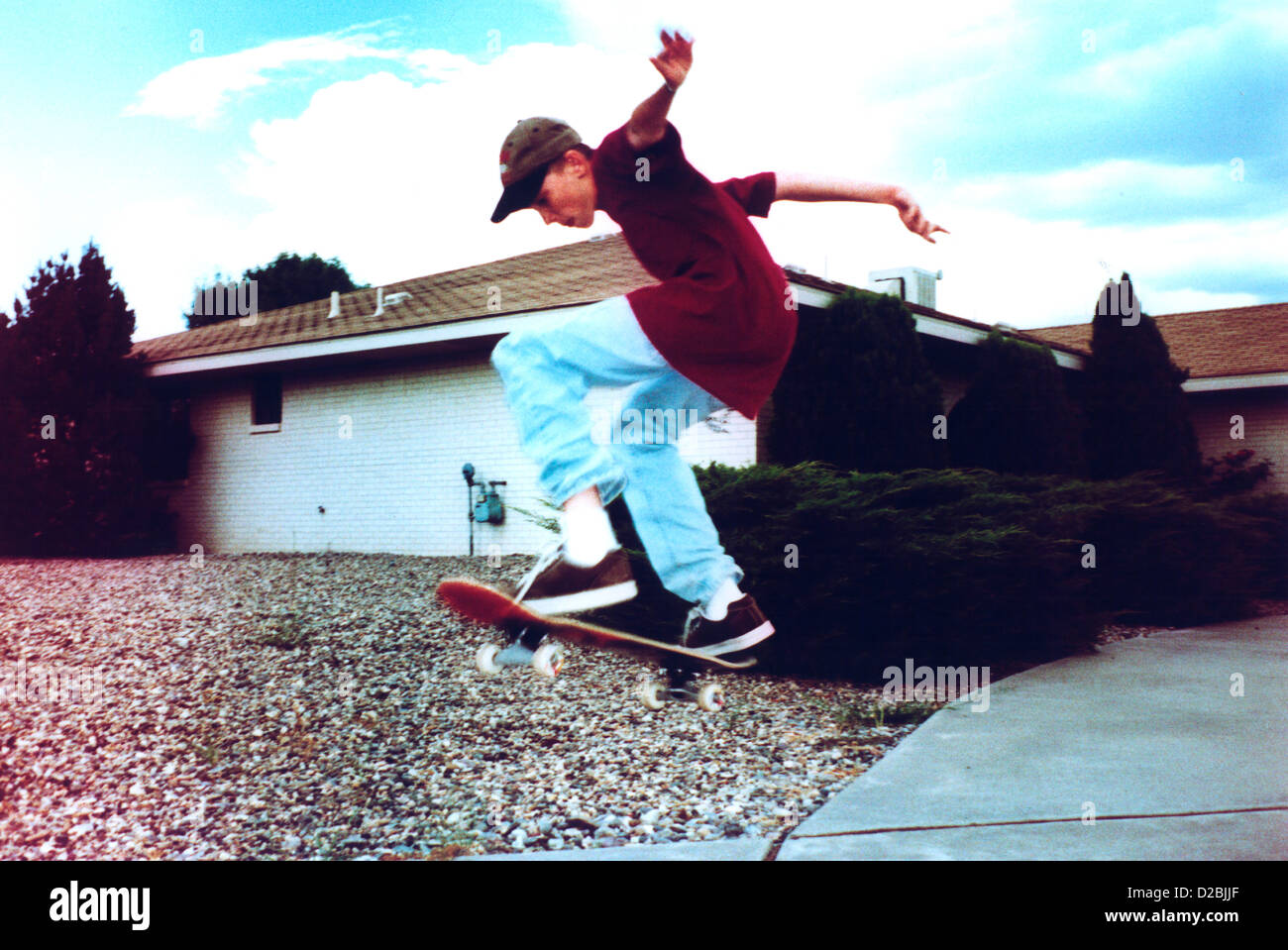 Suburban Boy Doing Jump On Skateboard Stock Photo - Alamy