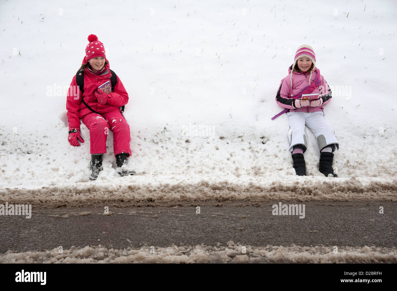 Young schoolgirls sitting on the roadside after a heavy fall of snow ...