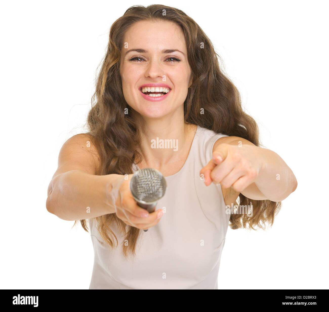 Happy young woman giving microphone and pointing in camera Stock Photo ...