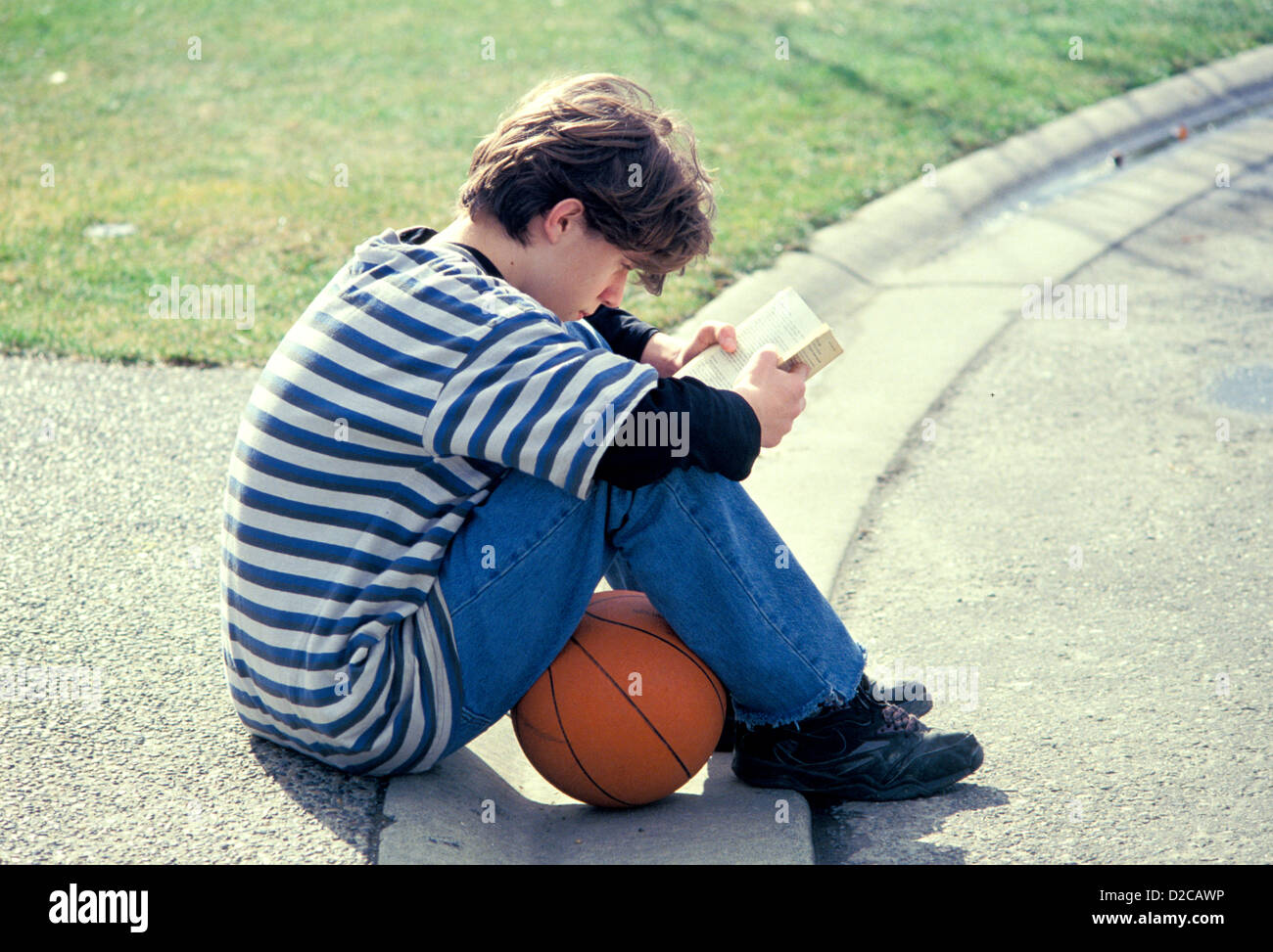 Teenage Boy Reading Outside, With Basketball Stock Photo - Alamy