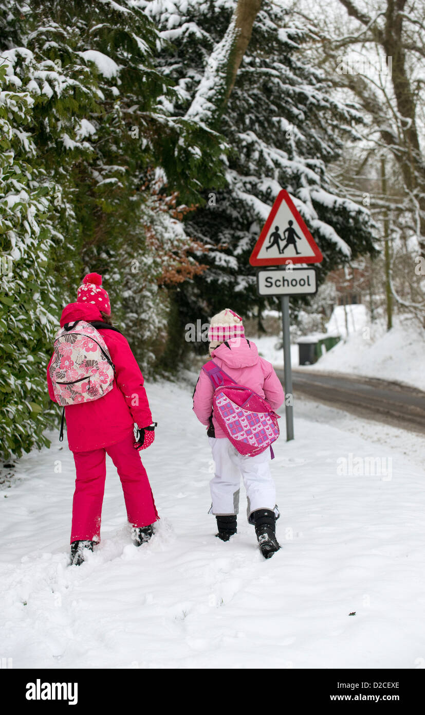 Children walking to school along a snow covered road with a school sign ...