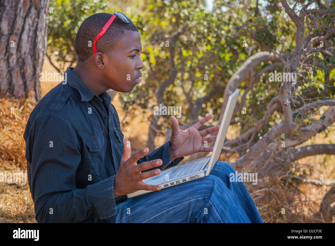 Smiling african student using a laptop outside Stock Photo - Alamy