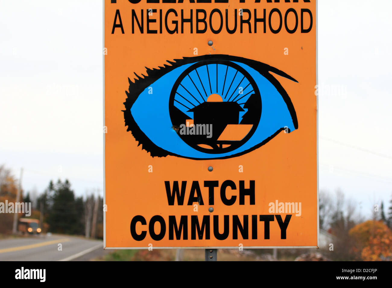 A neighborhood community watch sign beside a road with school bus in ...