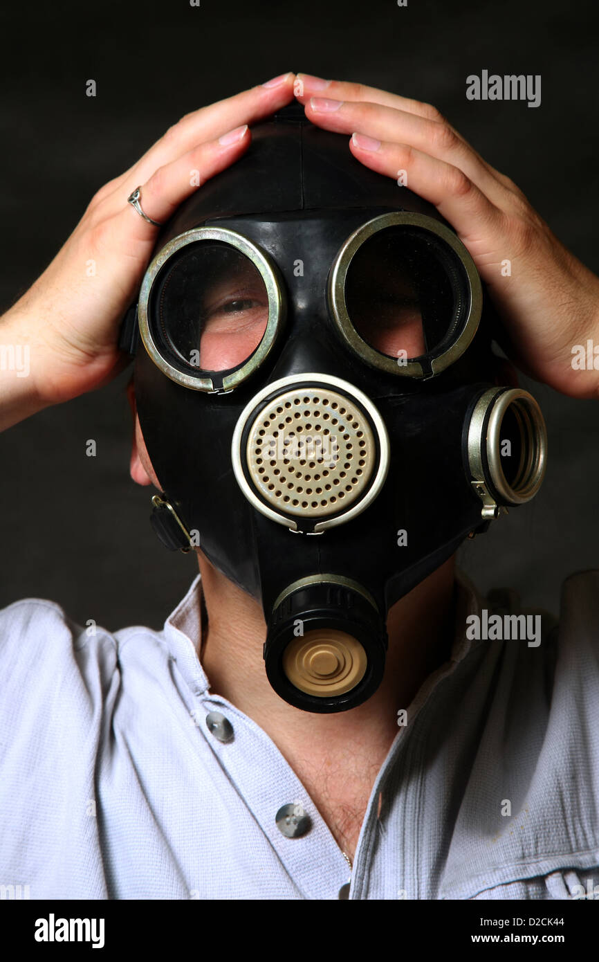 The person in a gas mask holds hands a head Stock Photo - Alamy