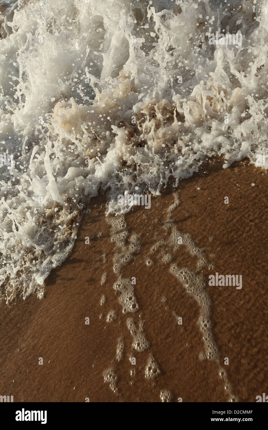 Detail of waves splashing on the edge of a sandy beach Stock Photo - Alamy